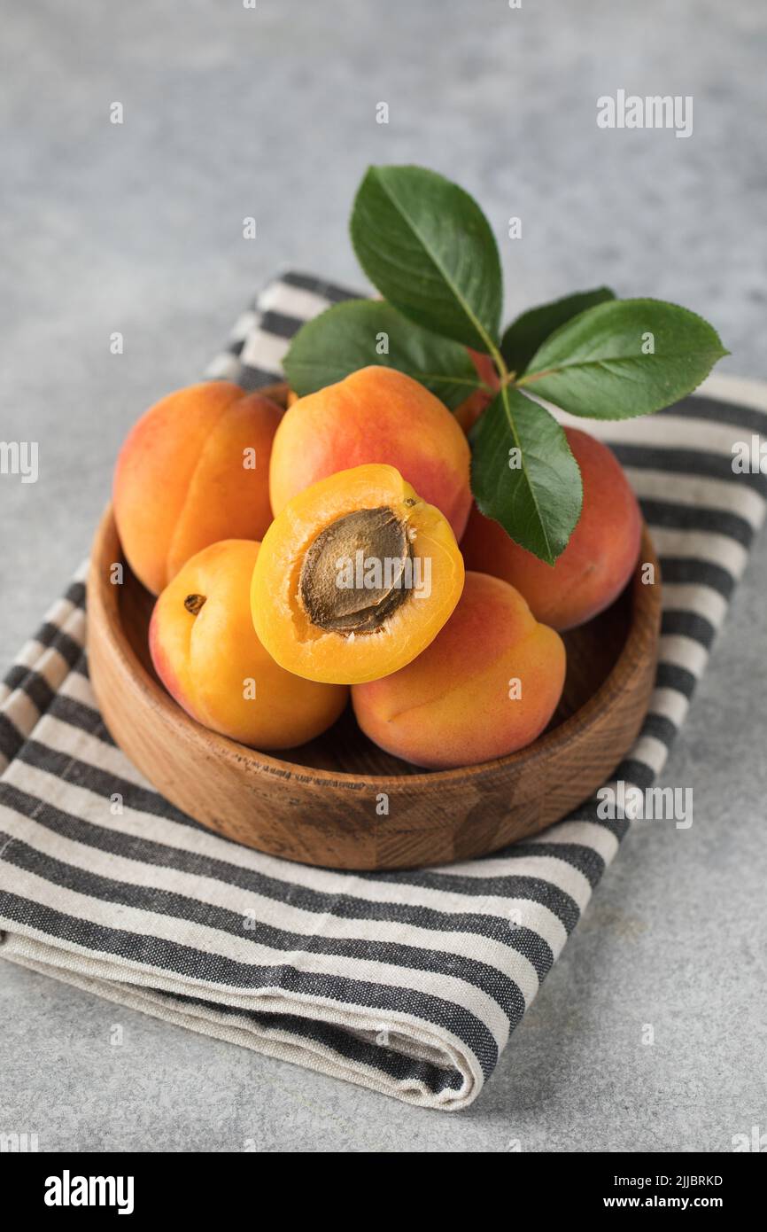 Ripe juicy apricots on a wooden plate on a gray background. Fresh fruit ...