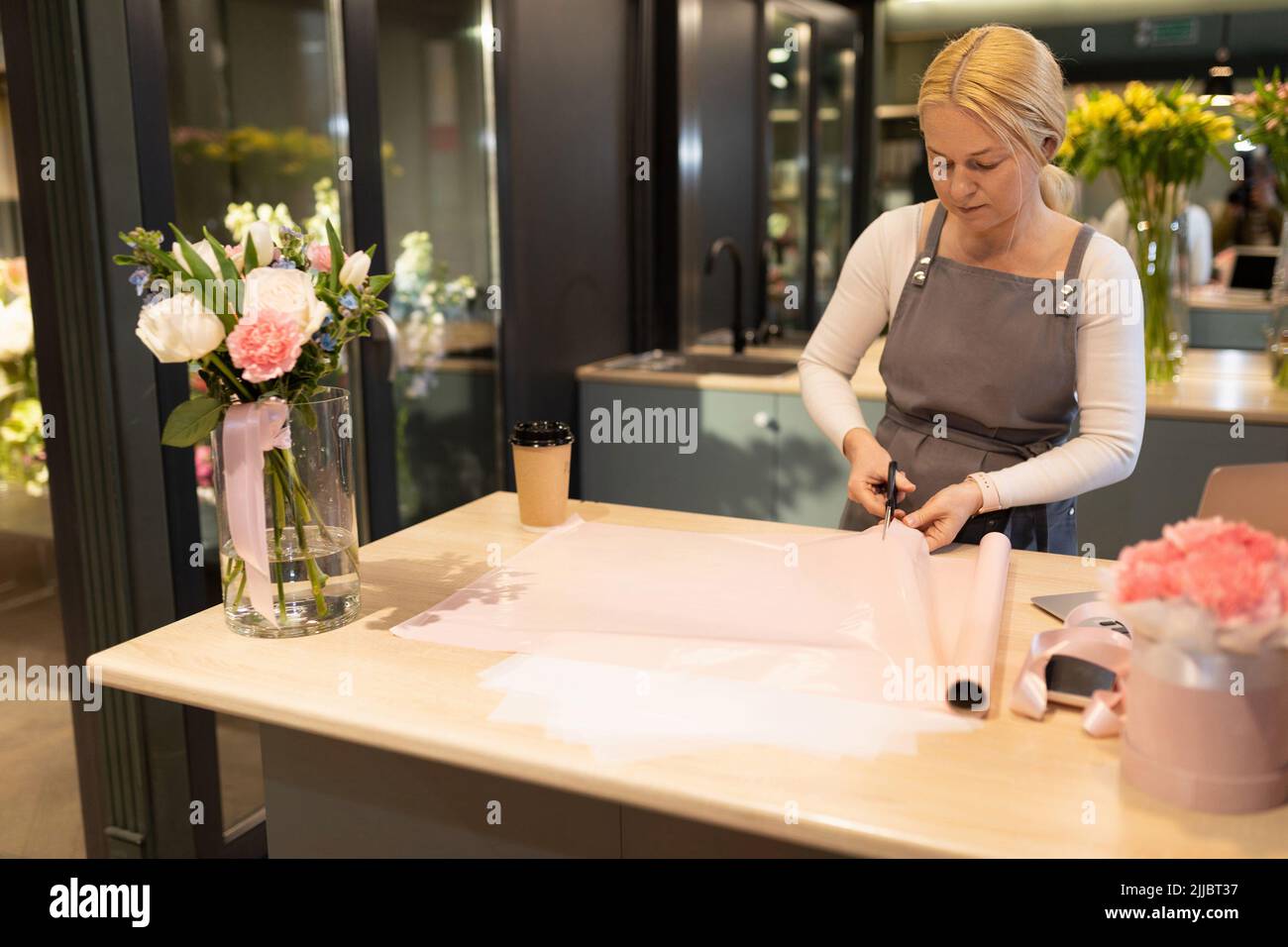 flower shop manager wrapping flowers in gift paper Stock Photo - Alamy