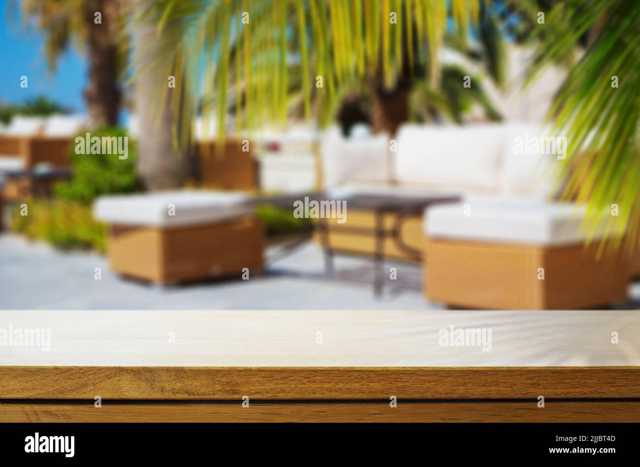 Empty wooden table on sunny blurred tropical hotel patio background ...