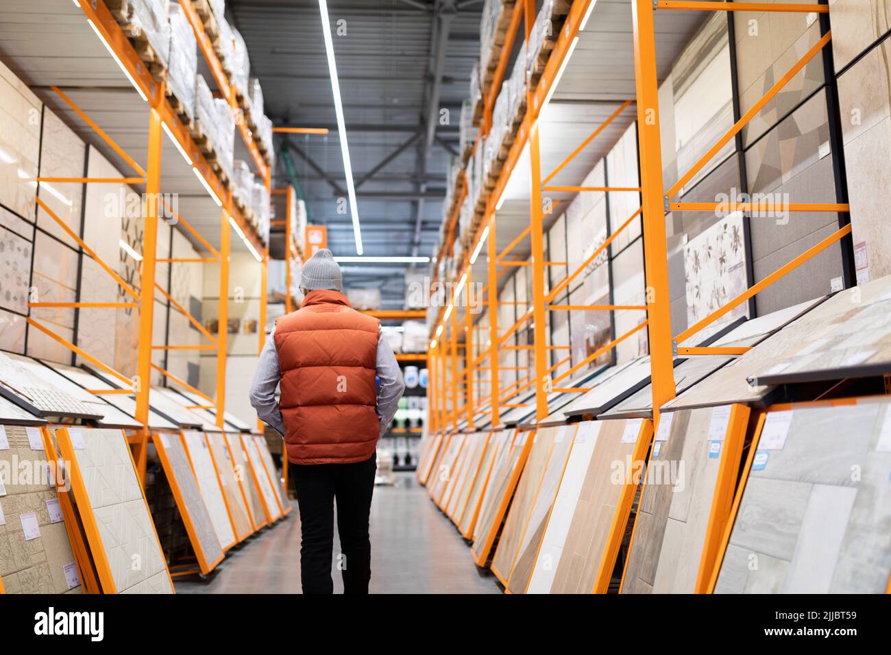 a customer walks in a hardware store between the rows with samples of ...