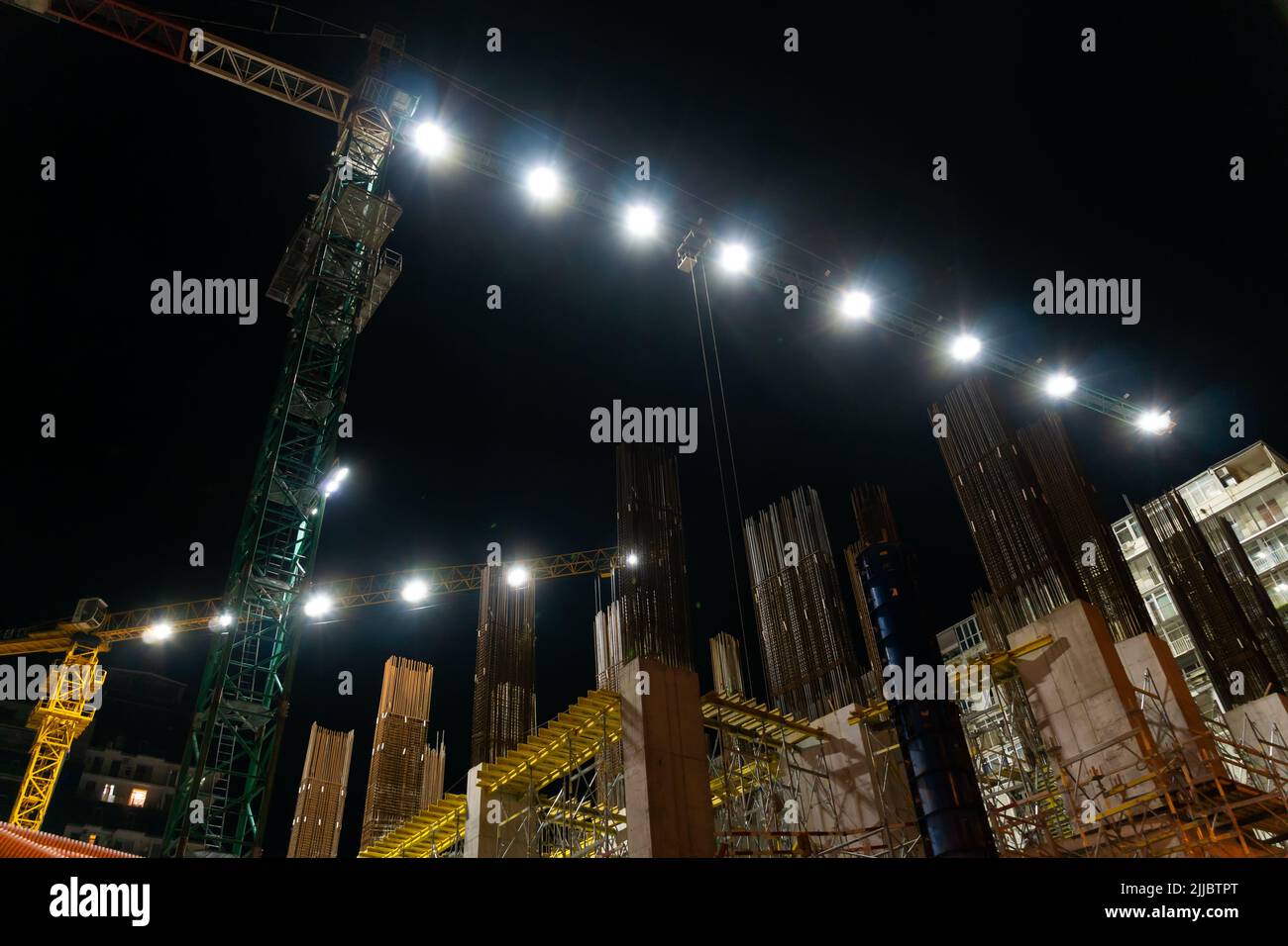 Illuminated construction cranes at night on the construction site Stock ...