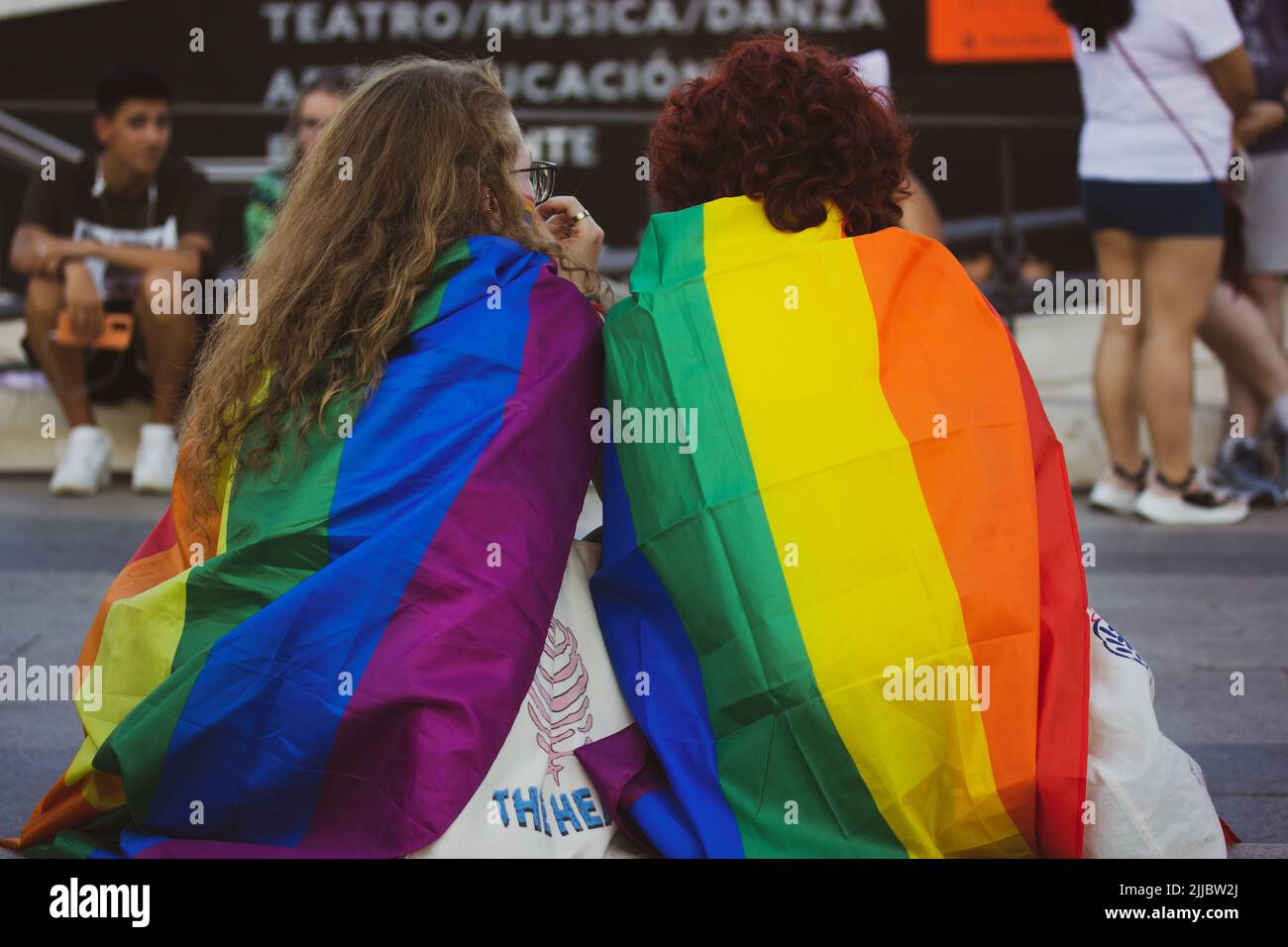 Madrid, Spain. July 25, 2022 Two girls, young women wrapped in rainbow ...