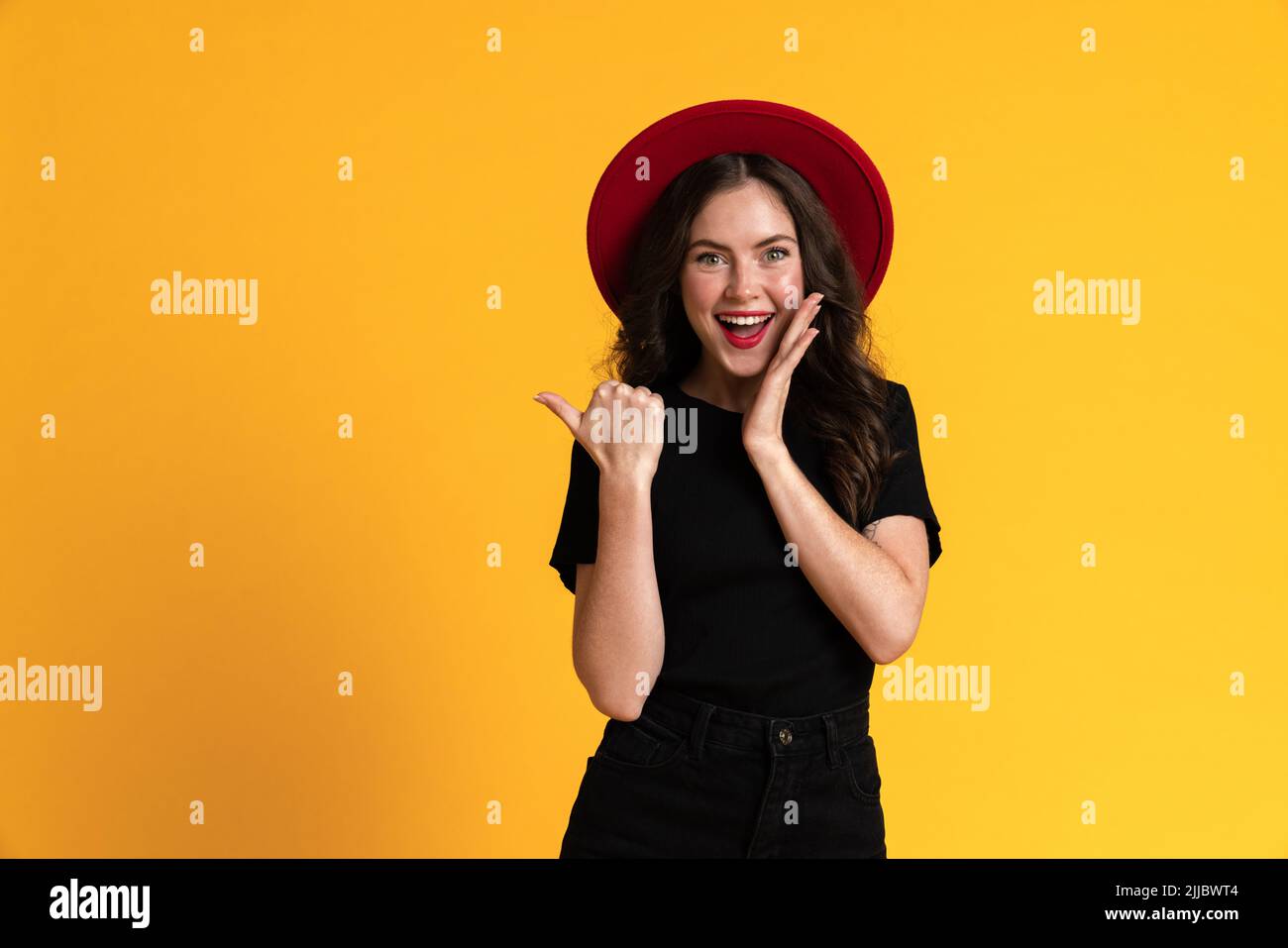 White young woman in red hat smiling while pointing finger aside ...