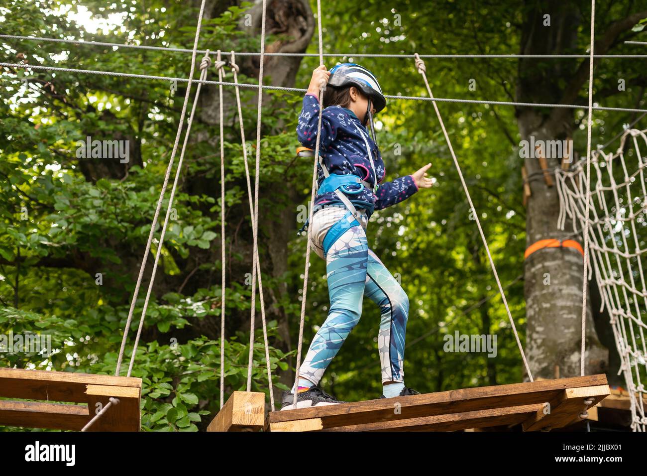 Little girl preschooler wearing full climbing harness having fun time ...