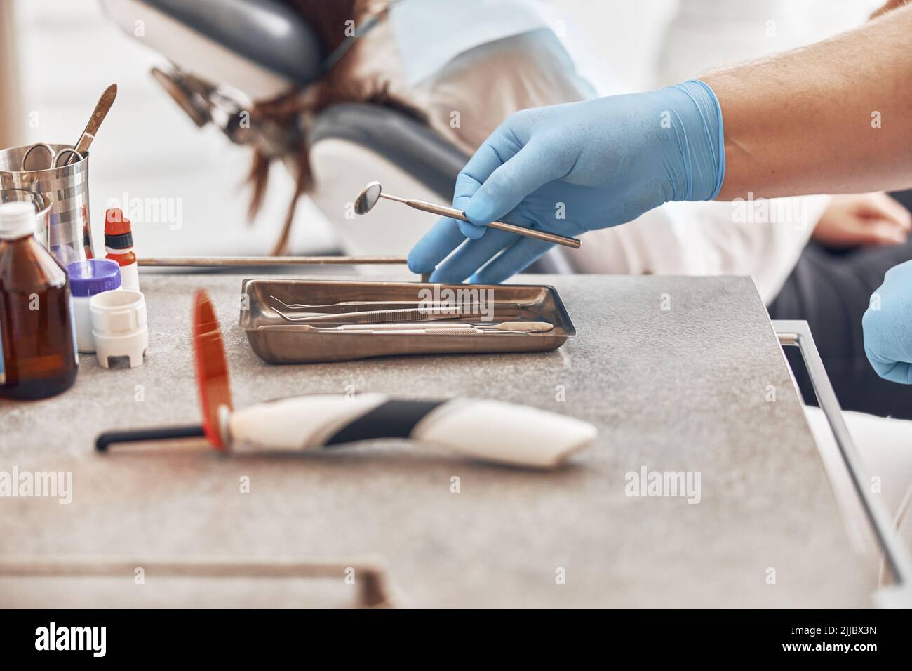 Hand in glove is holding dentist instrument in white modern cabinet ...