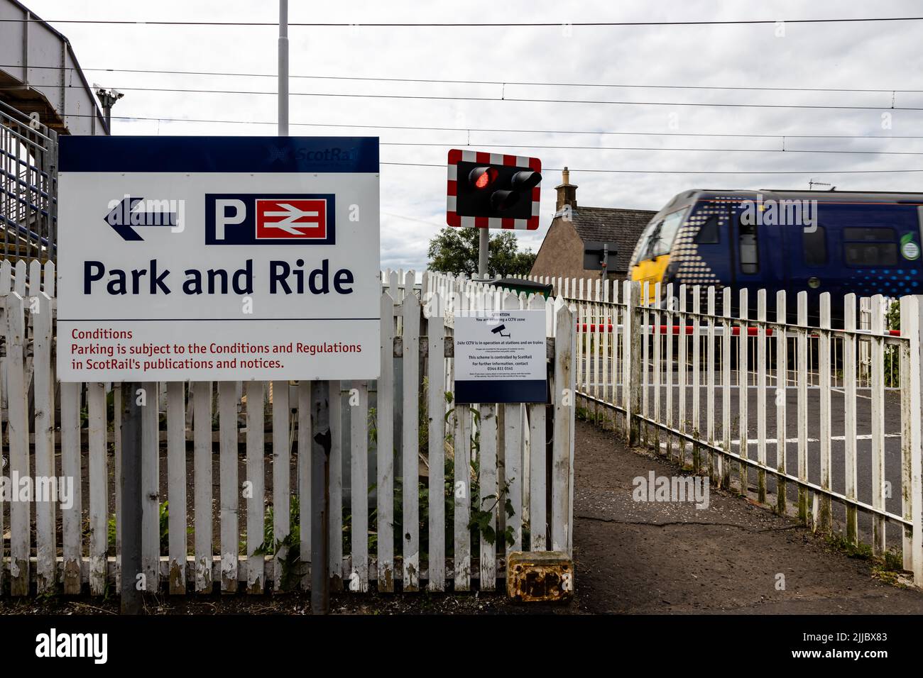 Park and Ride sign at a train station with train and level crossing ...