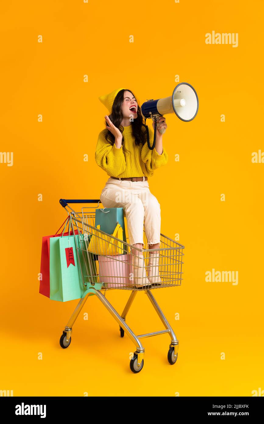 White woman screaming to megaphone while sitting in shopping cart ...