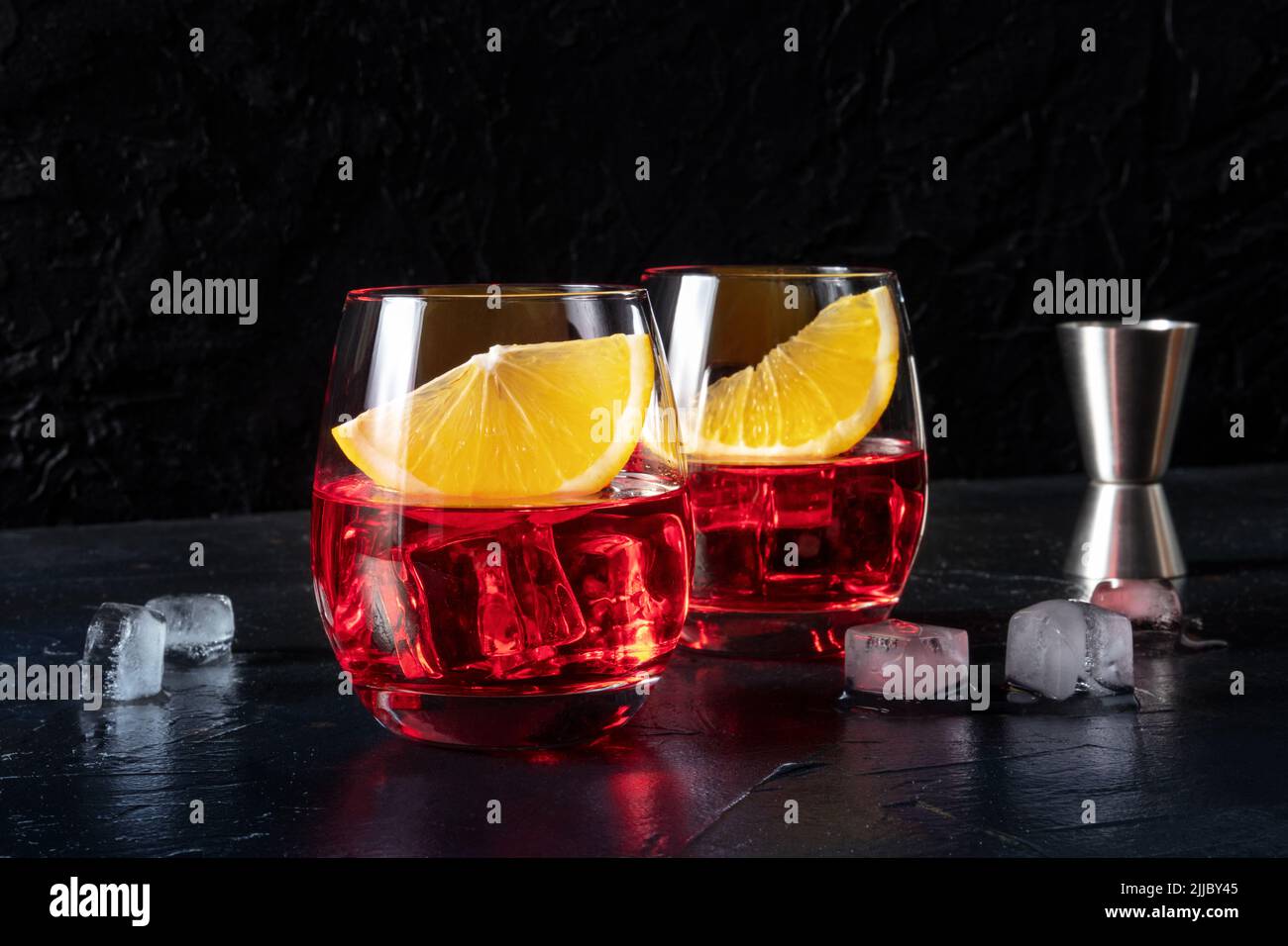 Campari aperitif with fresh orange slices and a jigger, on a black ...