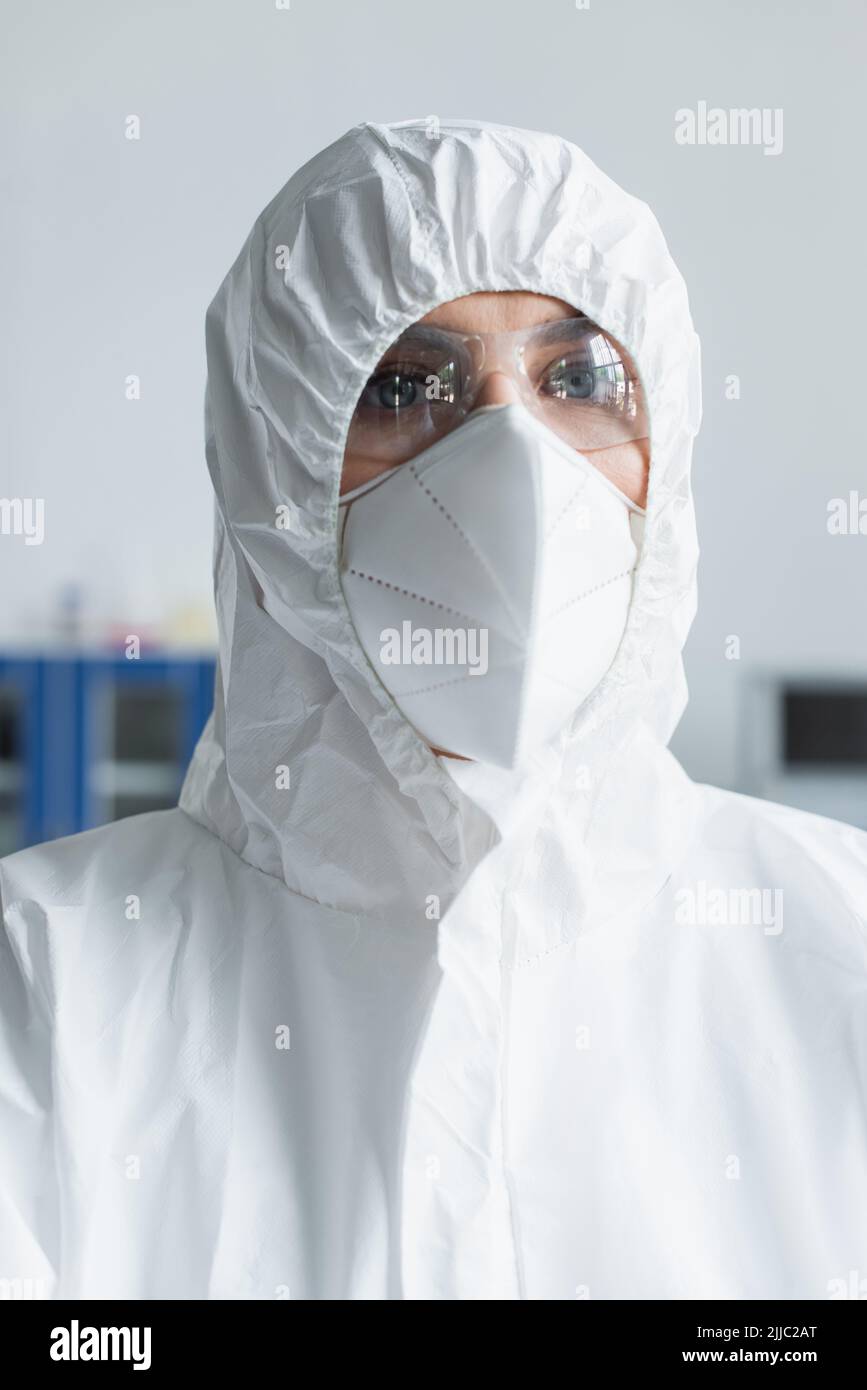 Portrait of scientist in hazmat suit and goggles looking at camera in ...
