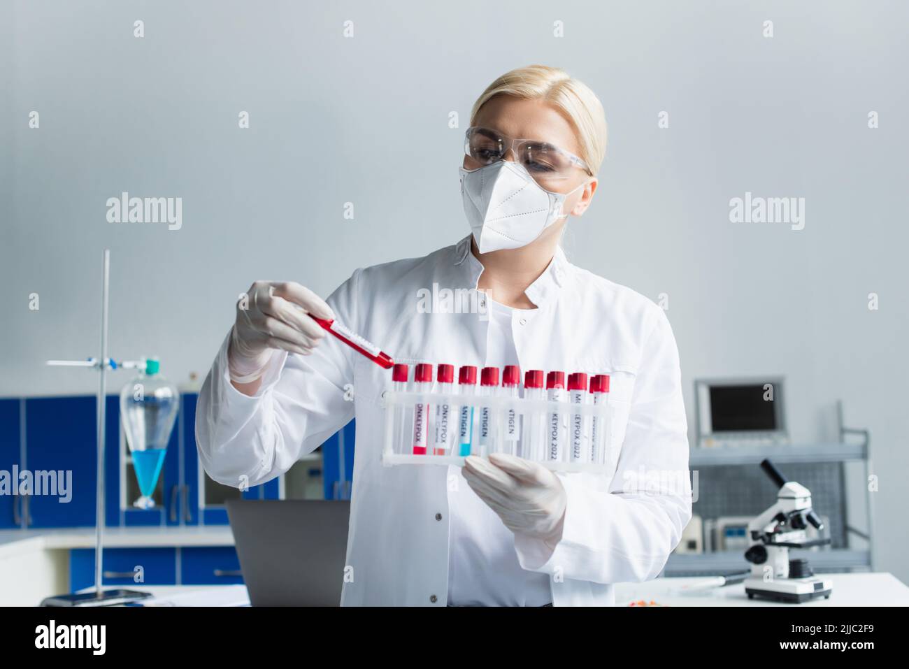 Researcher in protective mask holding test tubes with monkeypox ...