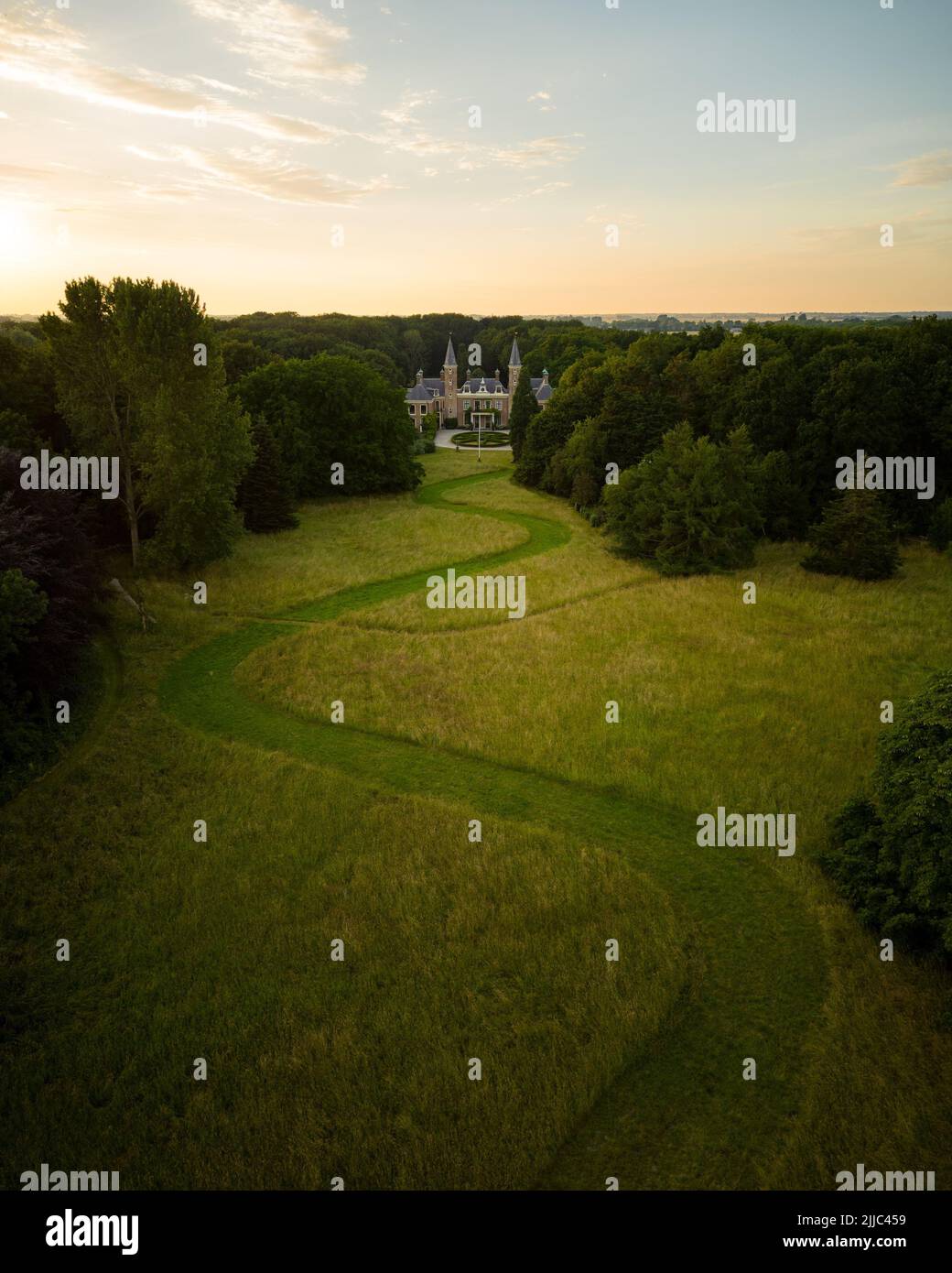 An aerial view of green winding road in the field leading to an old ...