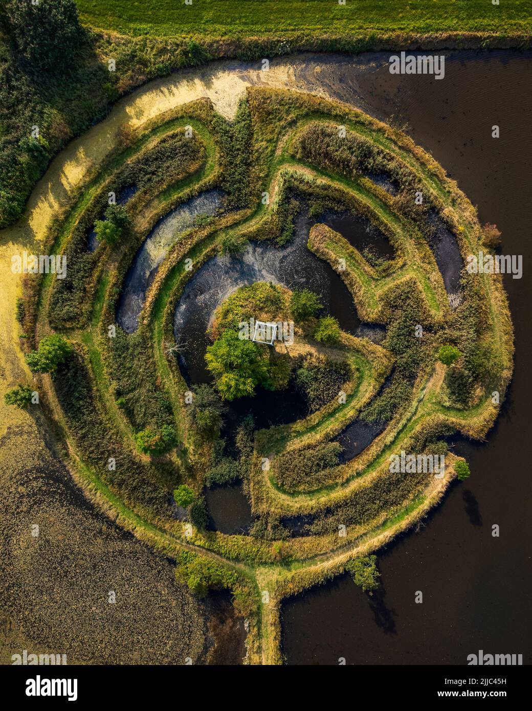 A vertical aerial view of green labyrinth garden by the lake Stock ...