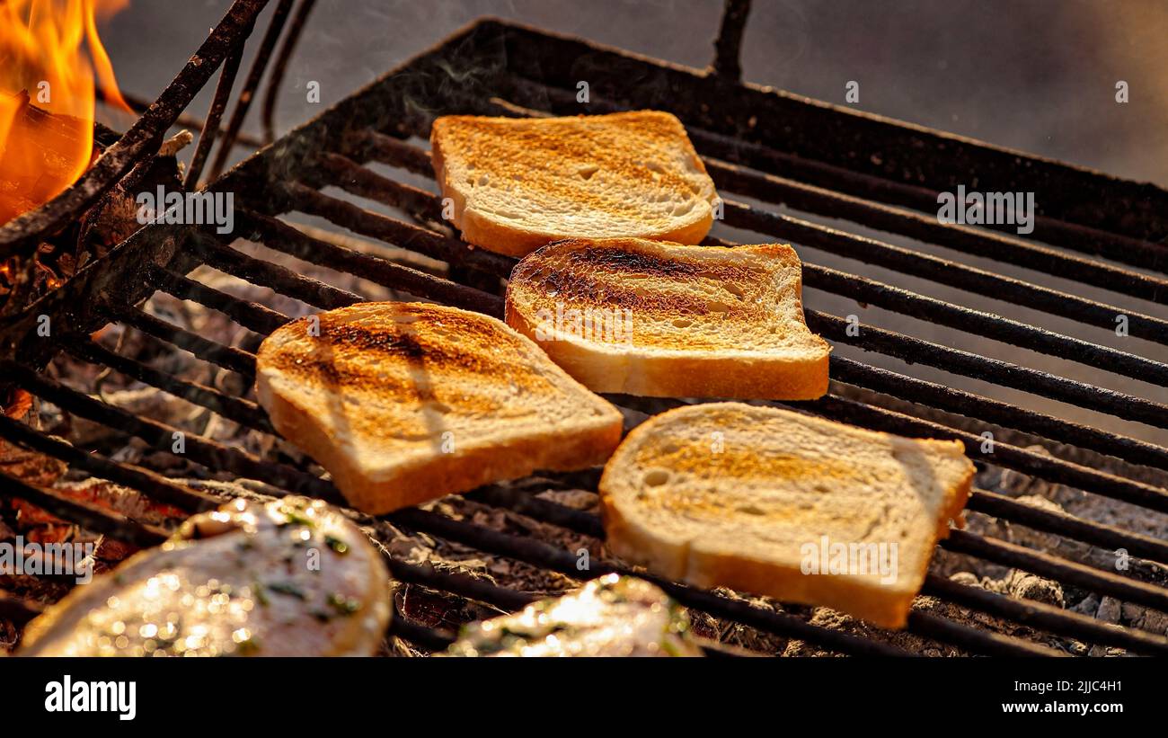 Pieces of white bread are grilling on the open fire outside, grill and ...