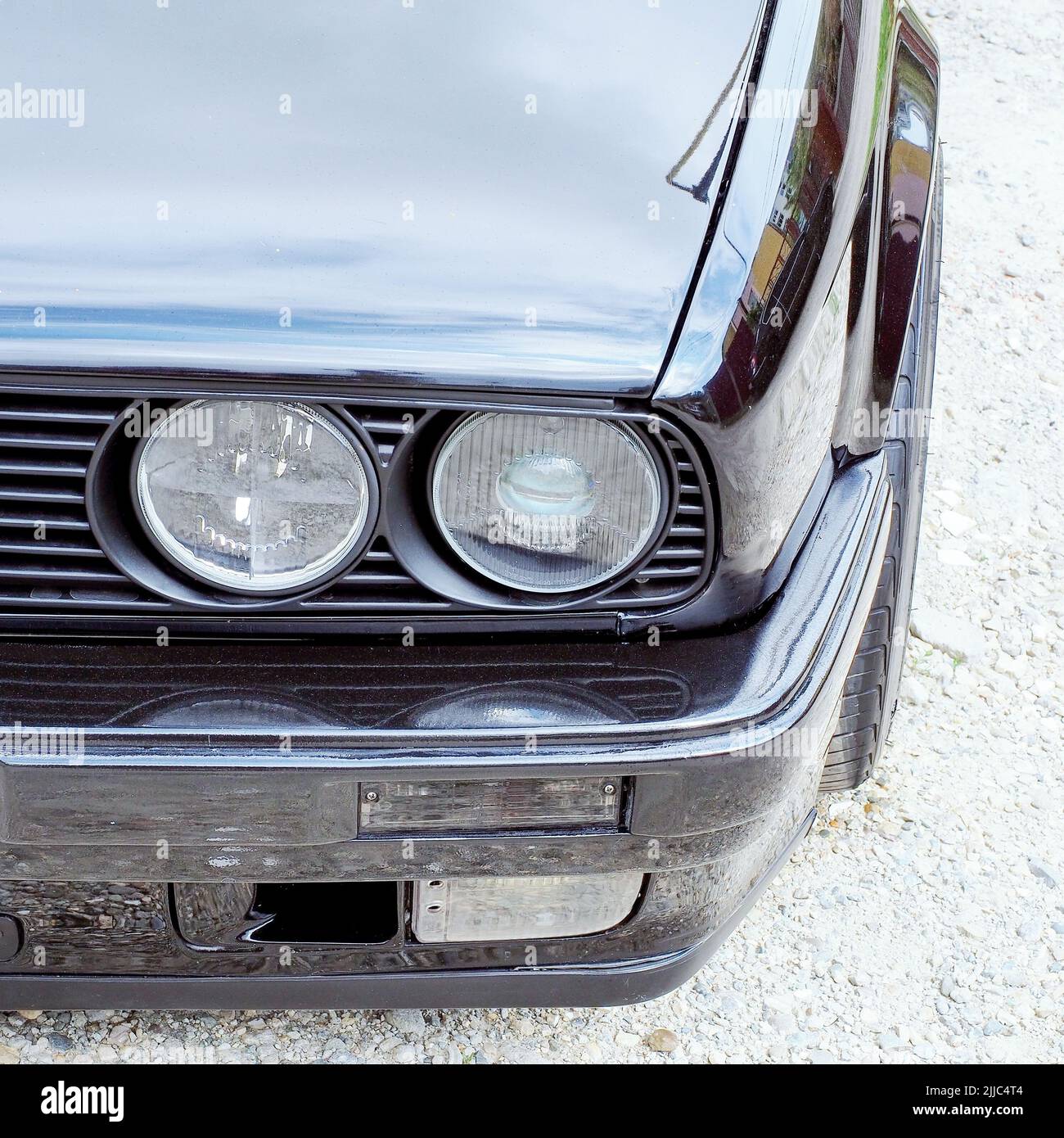 Round headlights of a glossy black car of the old model. Fragment of an ...