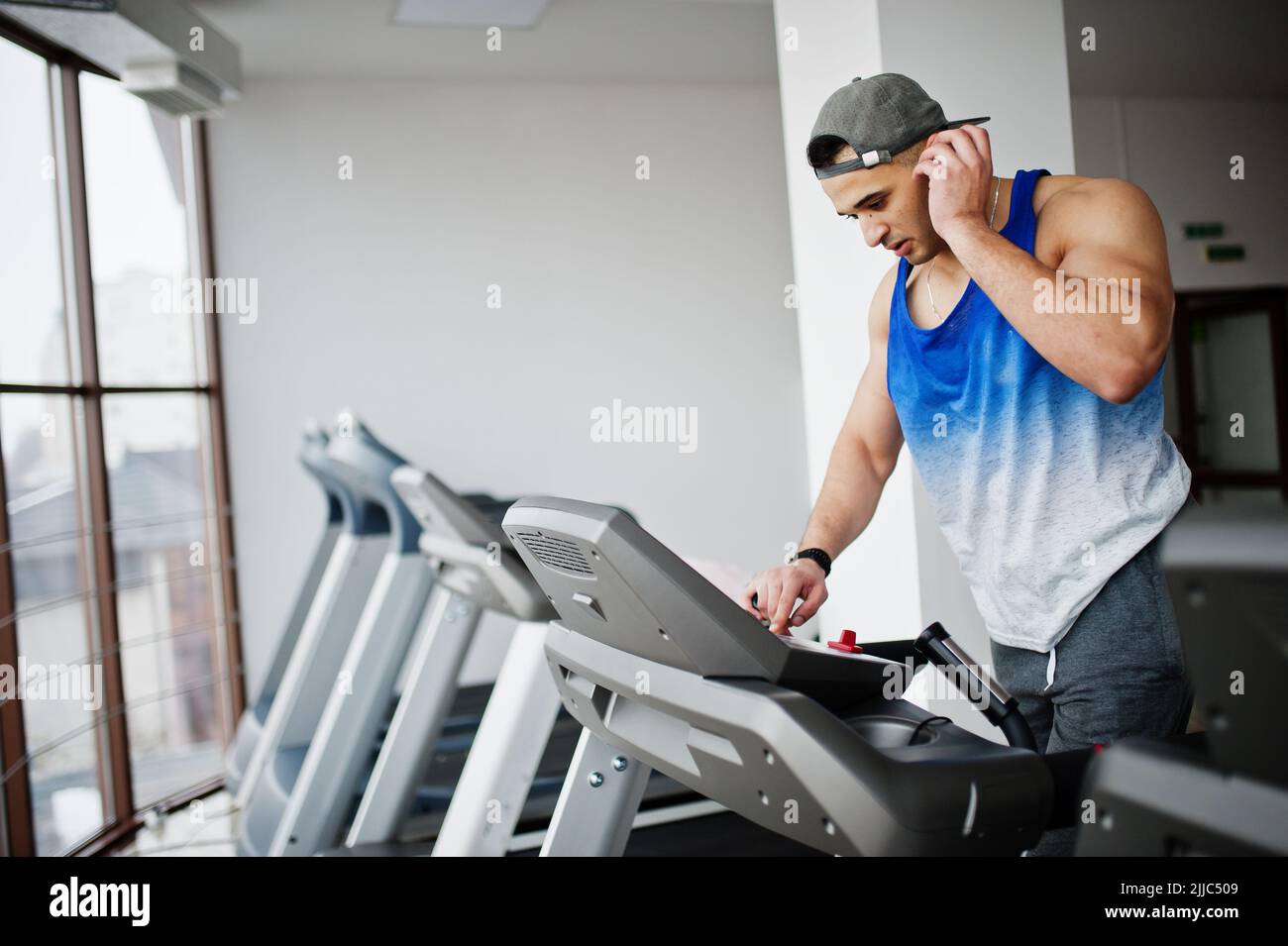 Fit and muscular arabian man running on treadmill in gym Stock Photo ...