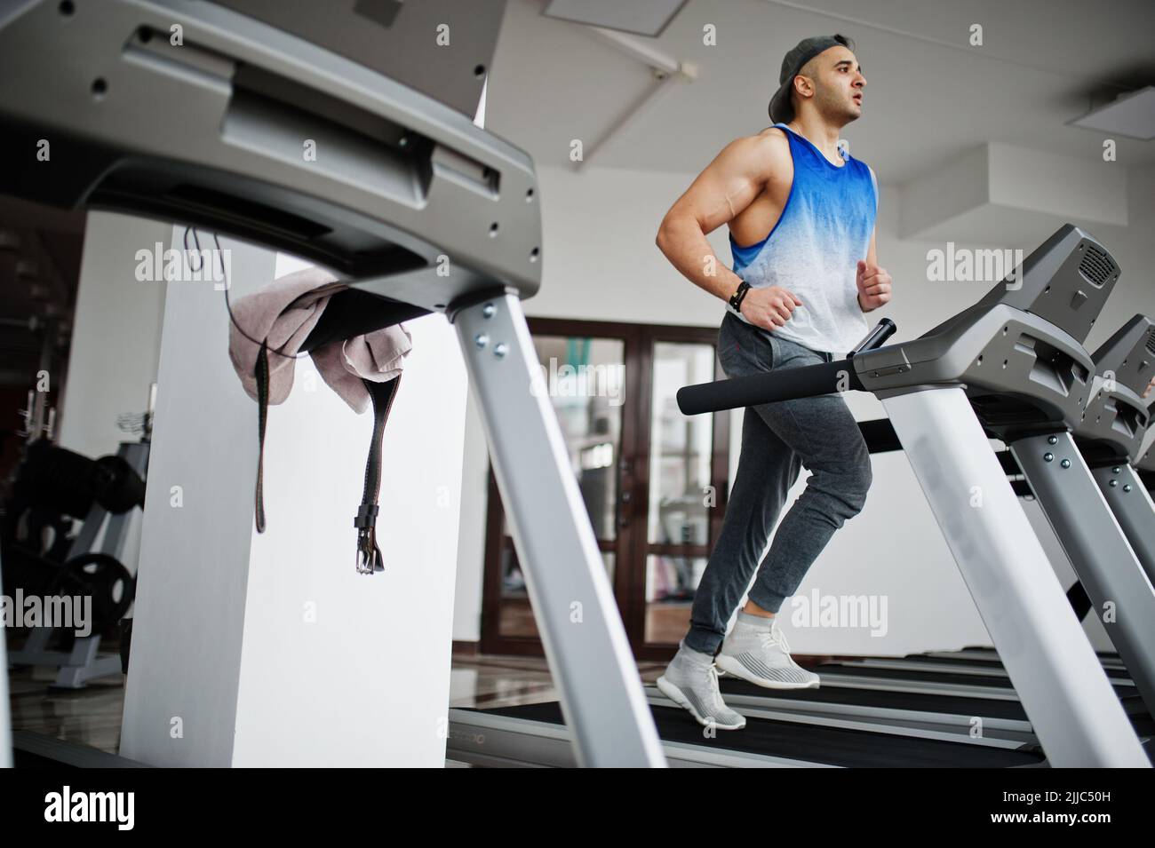 Fit and muscular arabian man running on treadmill in gym Stock Photo ...