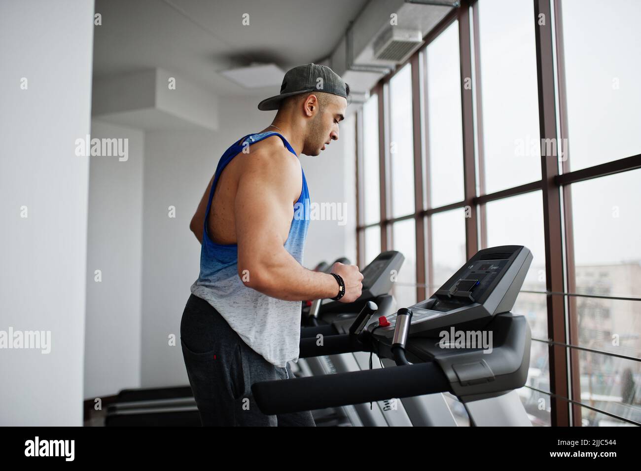 Fit and muscular arabian man running on treadmill in gym Stock Photo ...
