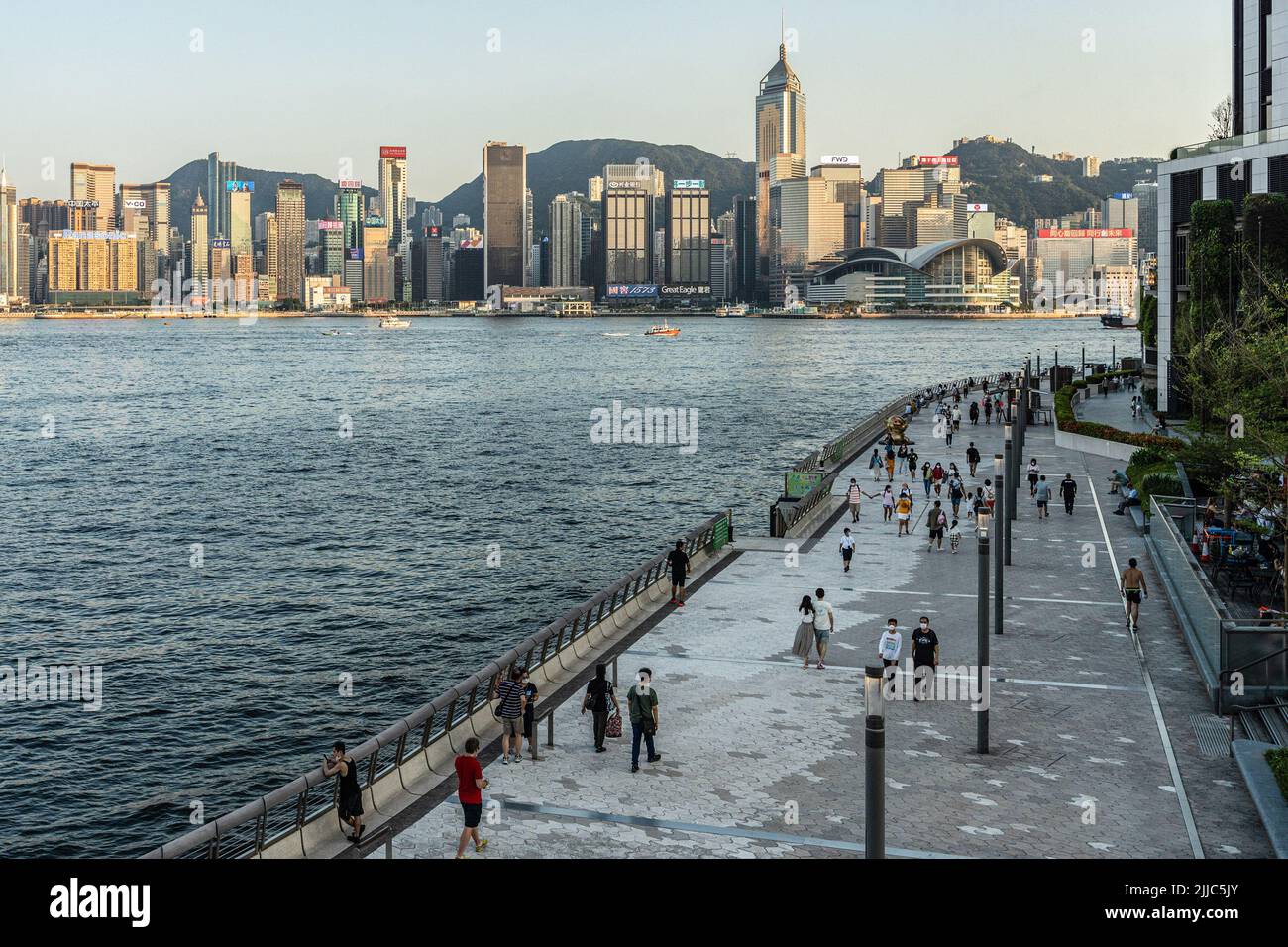 Pedestrians walk along the promenade at Victoria Harbour in the Tsim Sha Tsui district in Hong ...