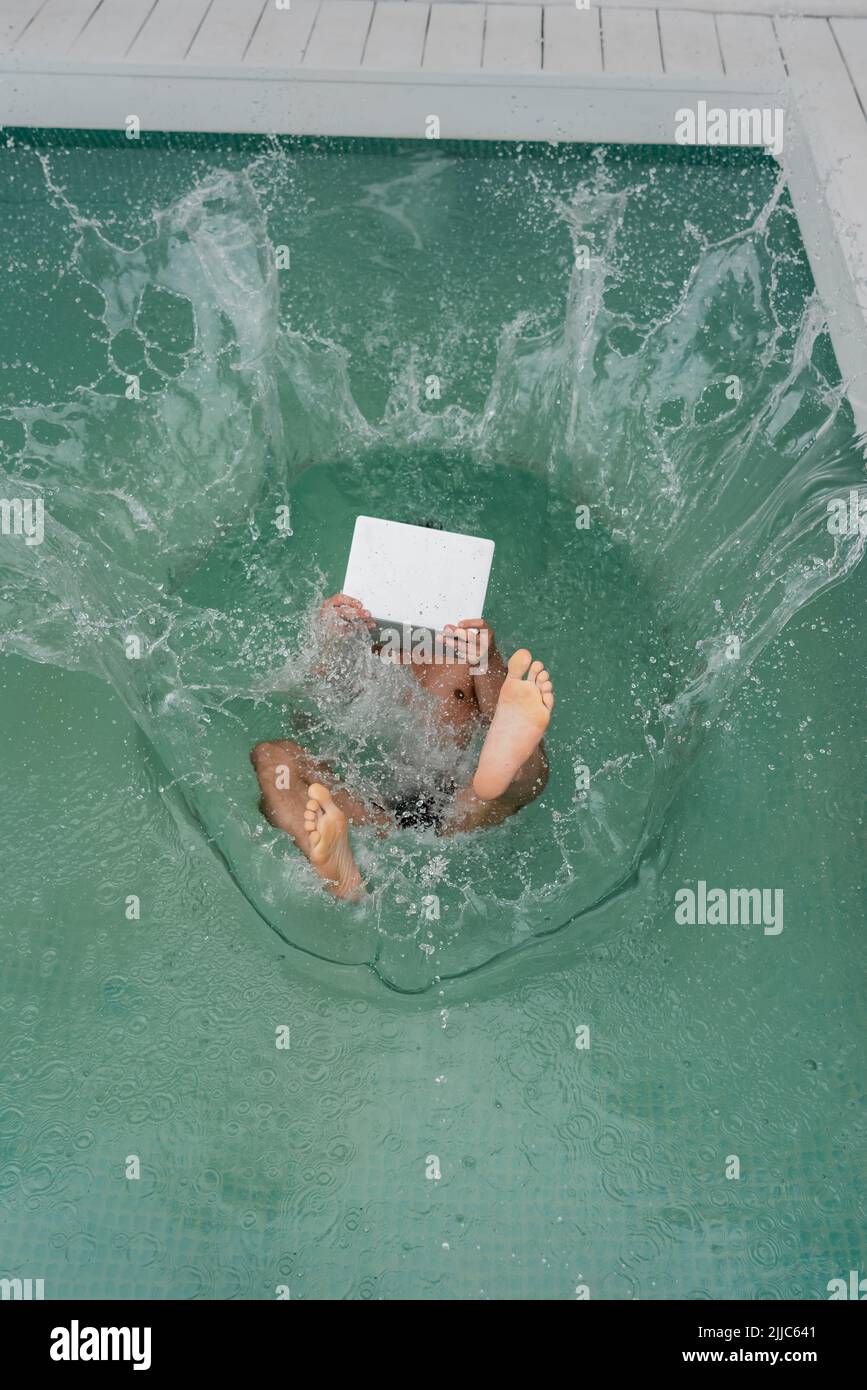 top view of freelance with laptop falling in pool with turquoise water ...