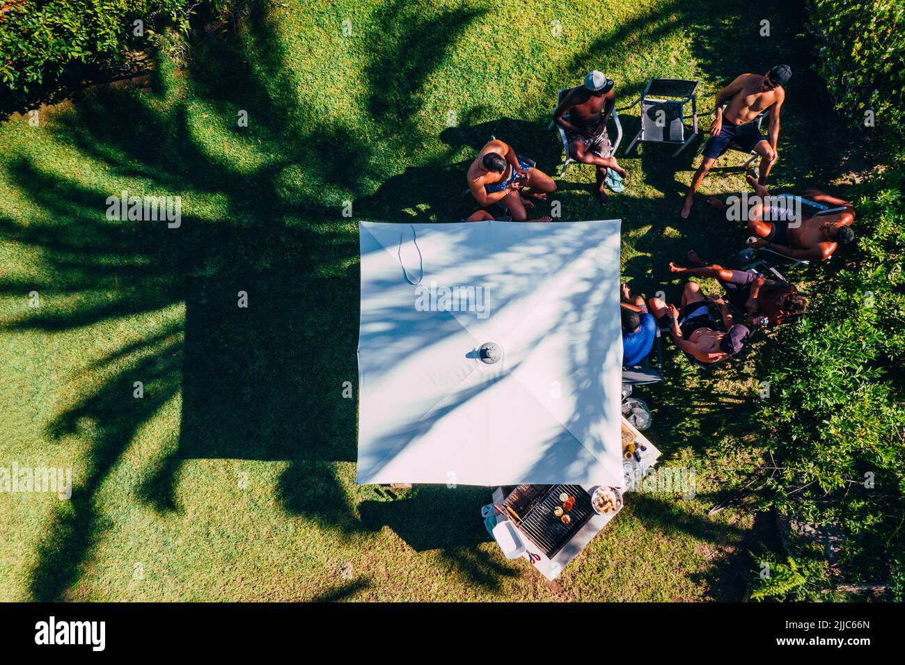 Top down view of friends sitting in a circle chatting during a barbecue ...