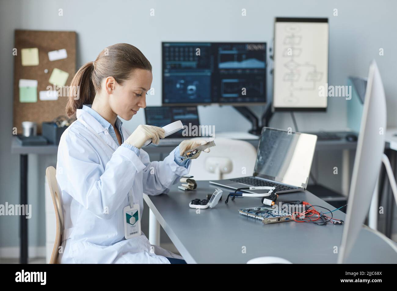 Side view portrait of young female scientist inspecting hardware with ...