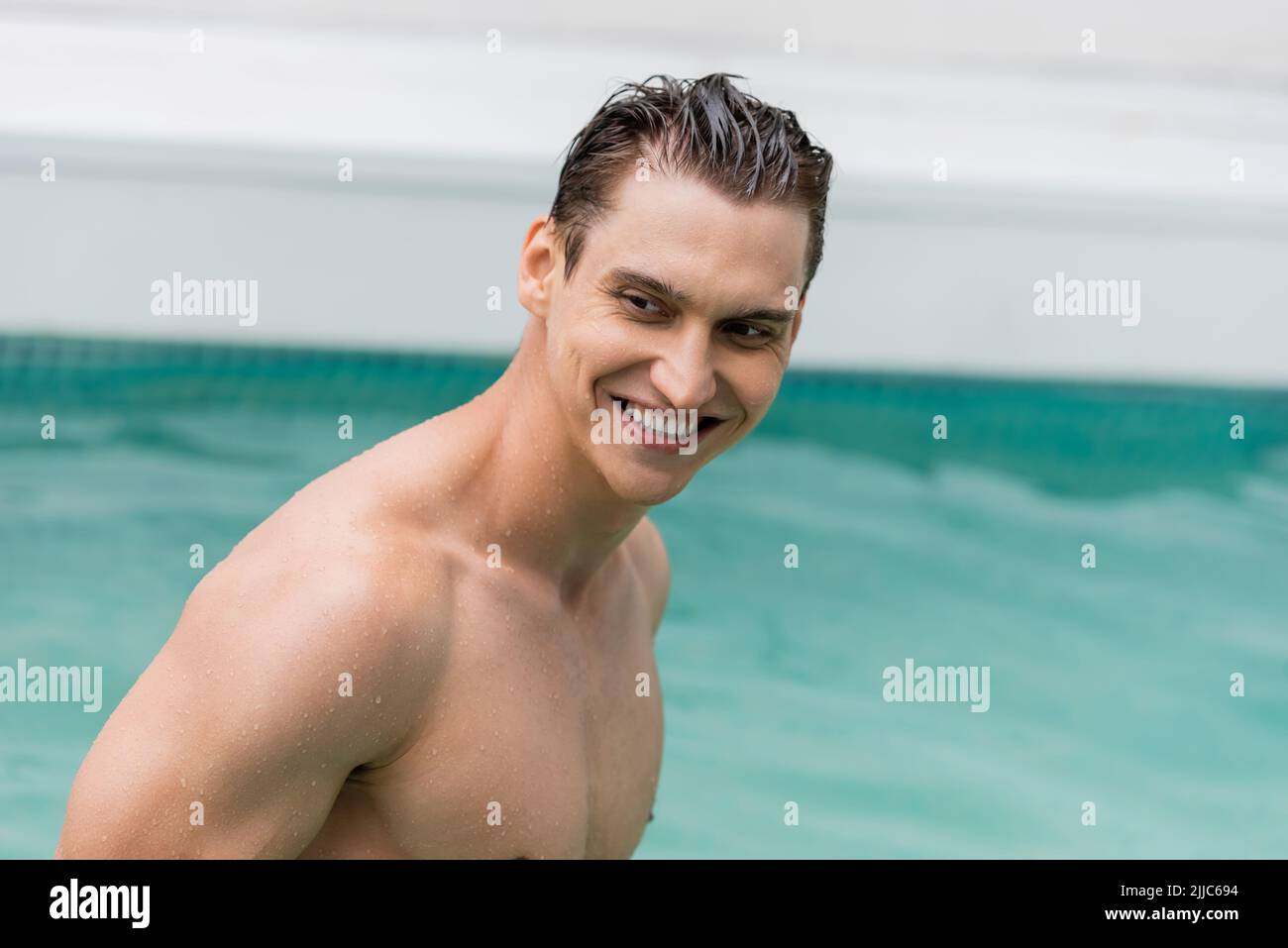 wet man with athletic body smiling and looking away in pool Stock Photo ...