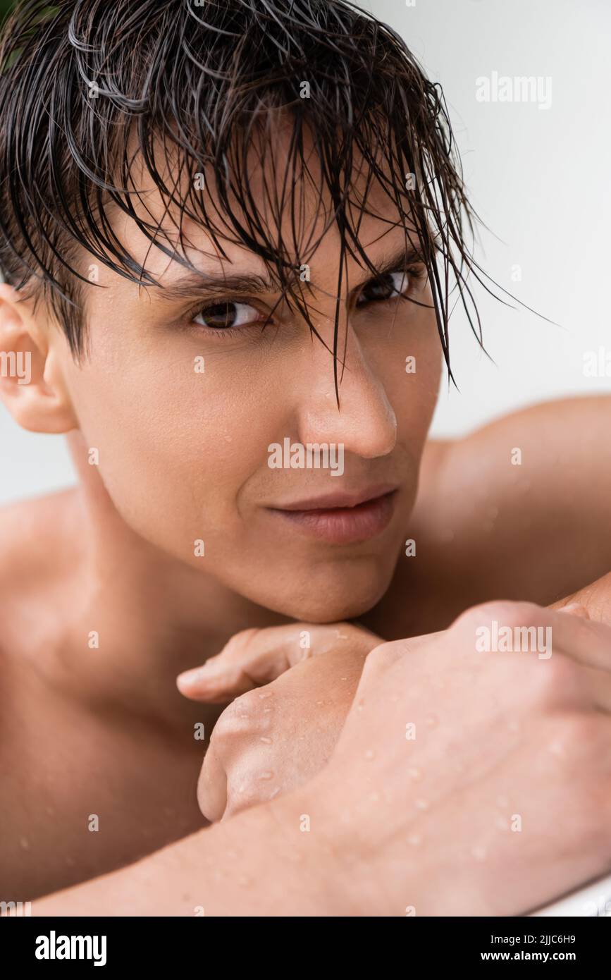 close up portrait of wet man with perfect skin looking at camera ...