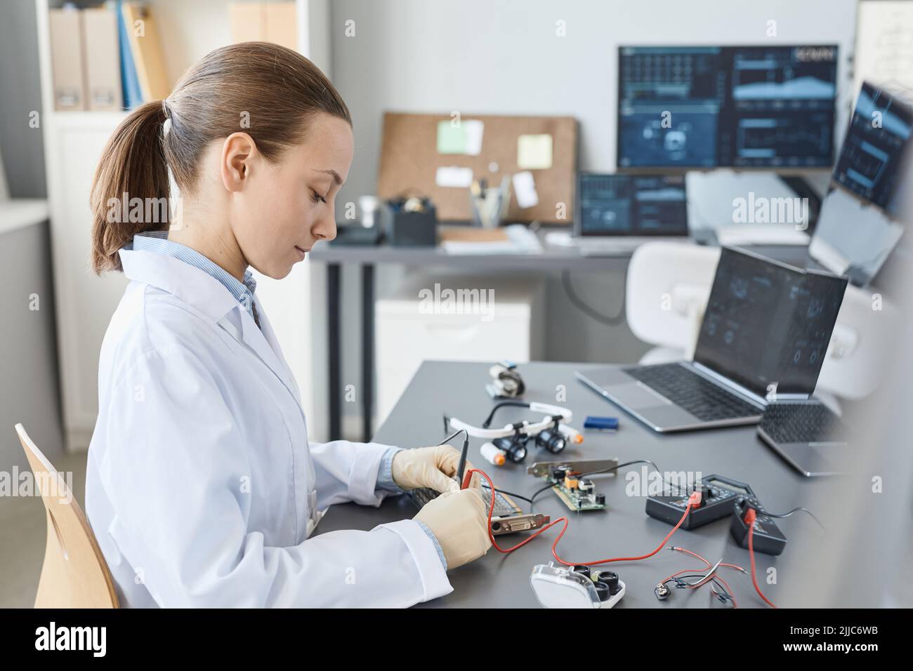 Side view portrait of female lab technician checking hardware parts at ...