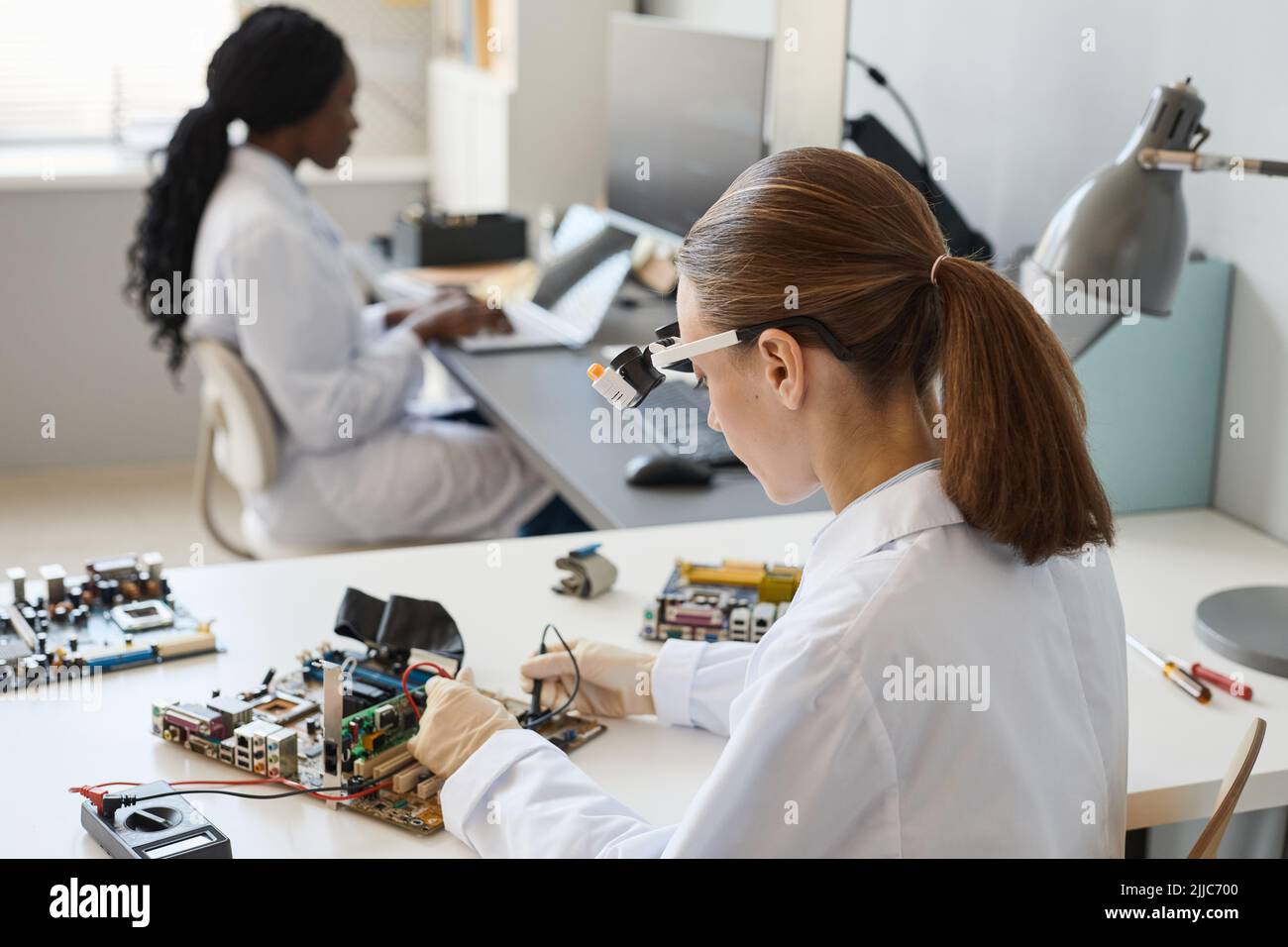 Back view portrait of female engineer working with hardware parts in ...