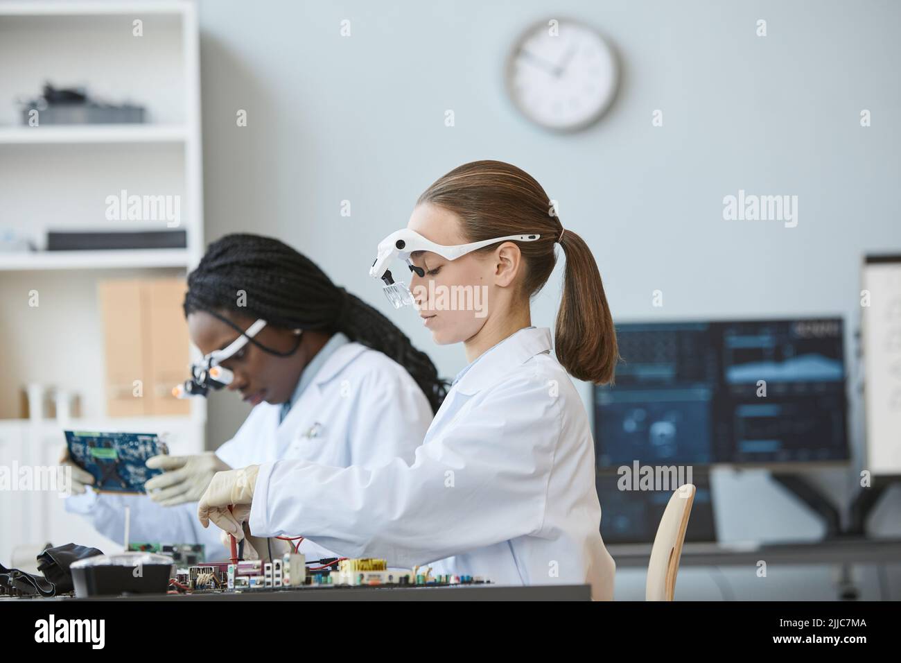 Side view portrait of two female engineers working with electronic ...