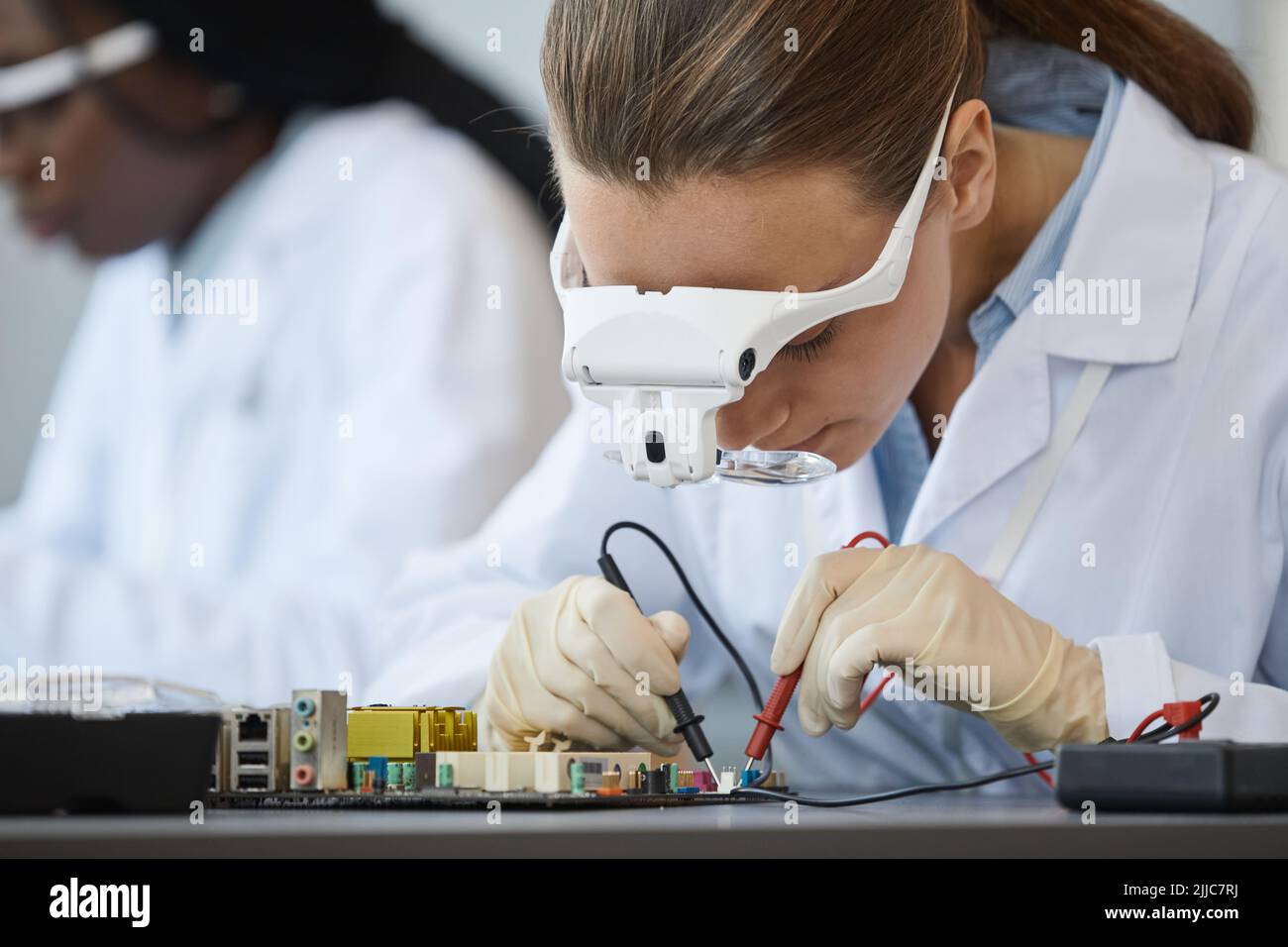 Close up portrait of young female engineer inspecting computer parts ...