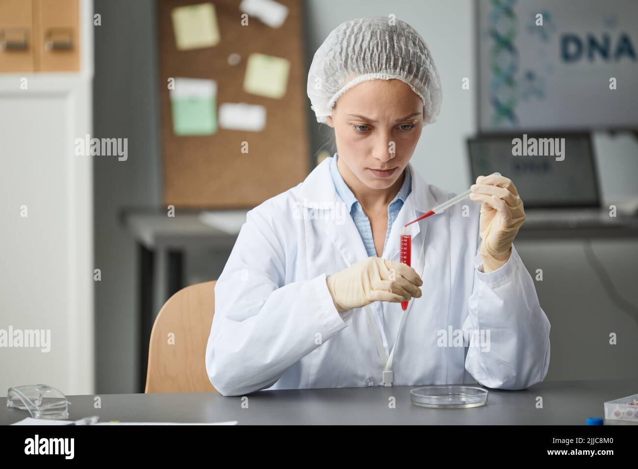 Portrait of female lab technician performing experiments with red ...