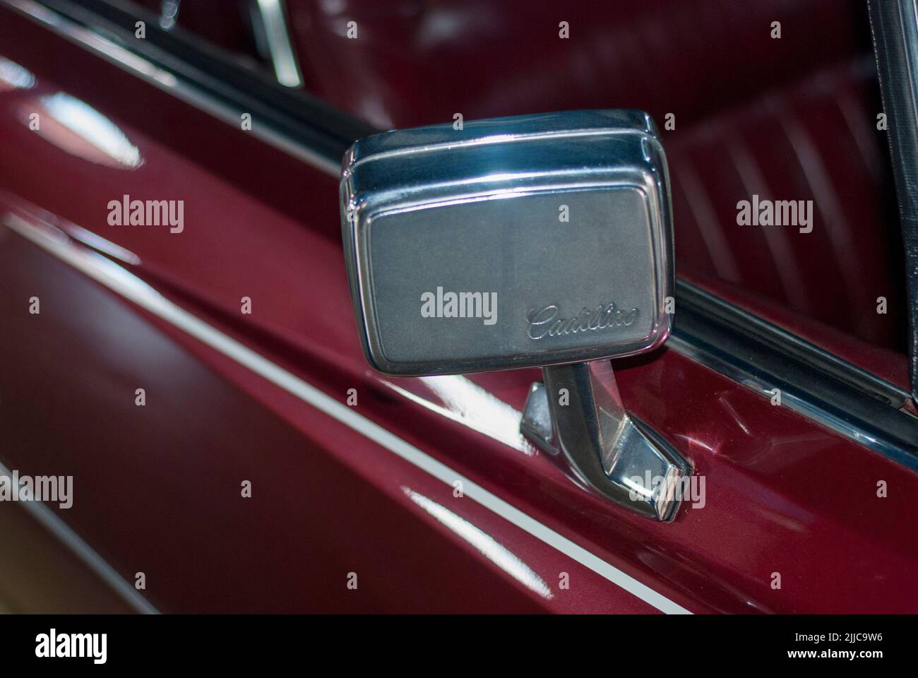 Cadillac metal rearview mirror detail with car in maroon, gold Stock ...