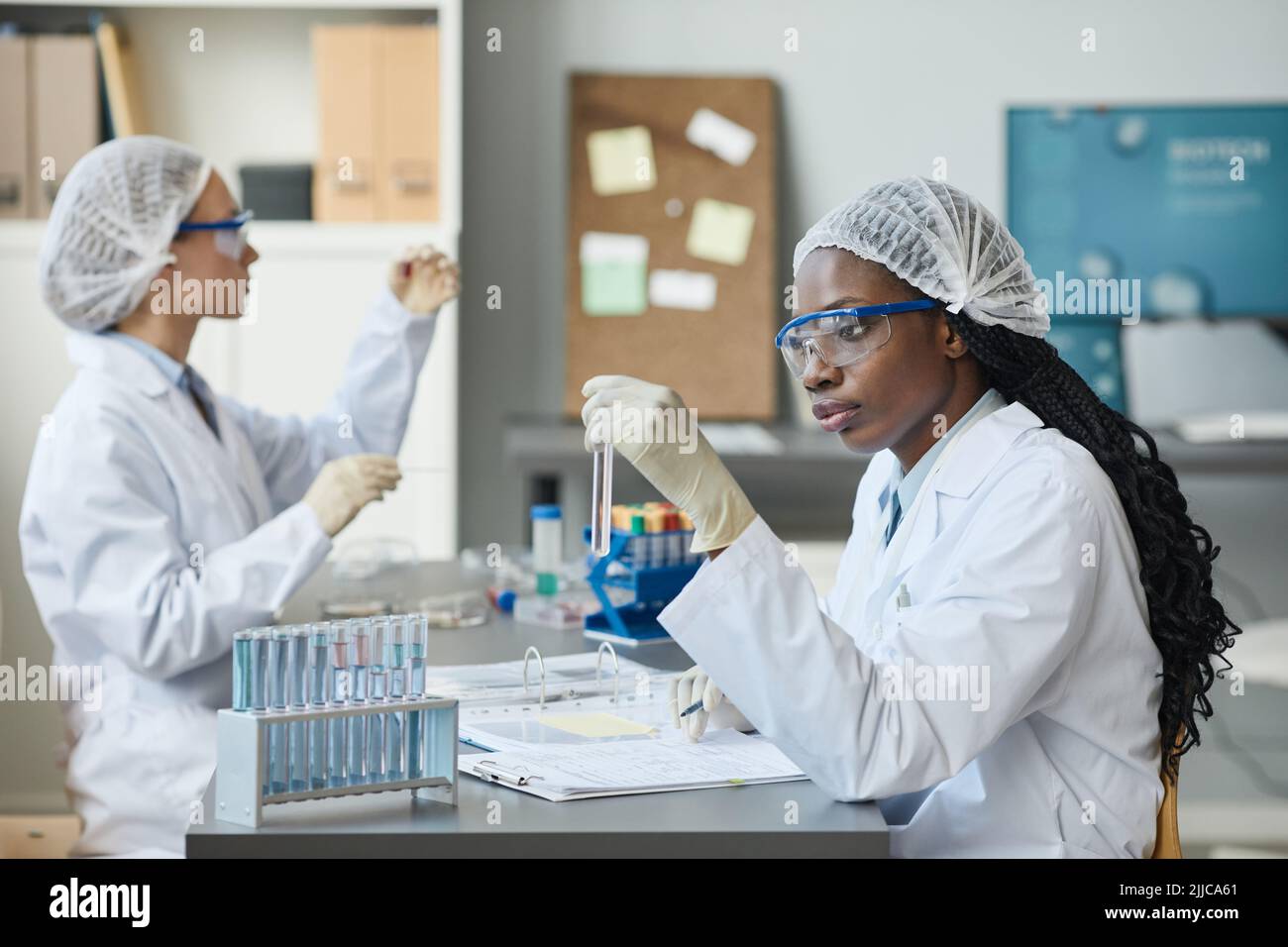 Portrait of female lab technician performing experiments with liquid at ...