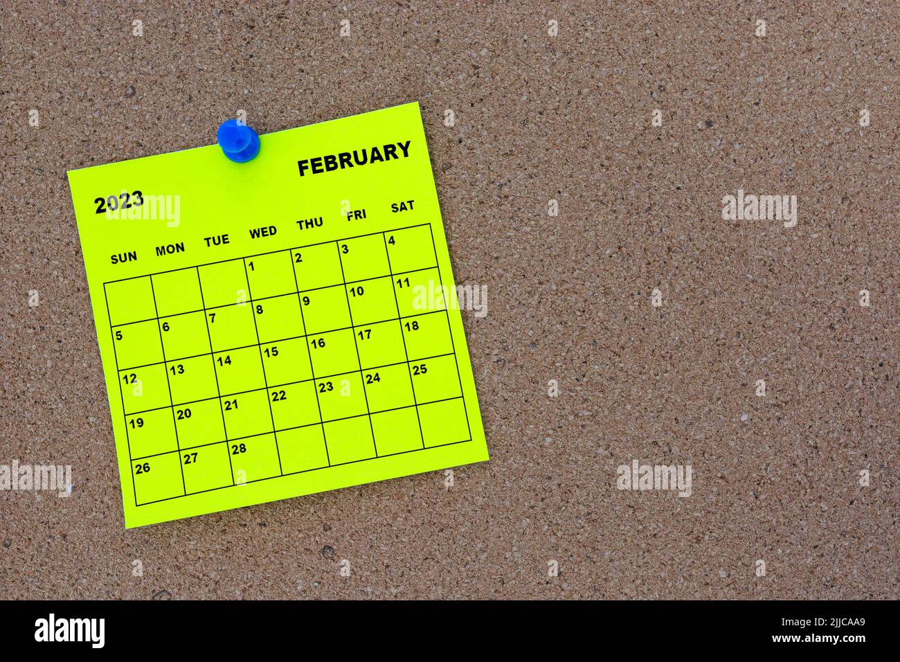 February 2023 yellow sticky note calendar with pin on cork bulletin ...