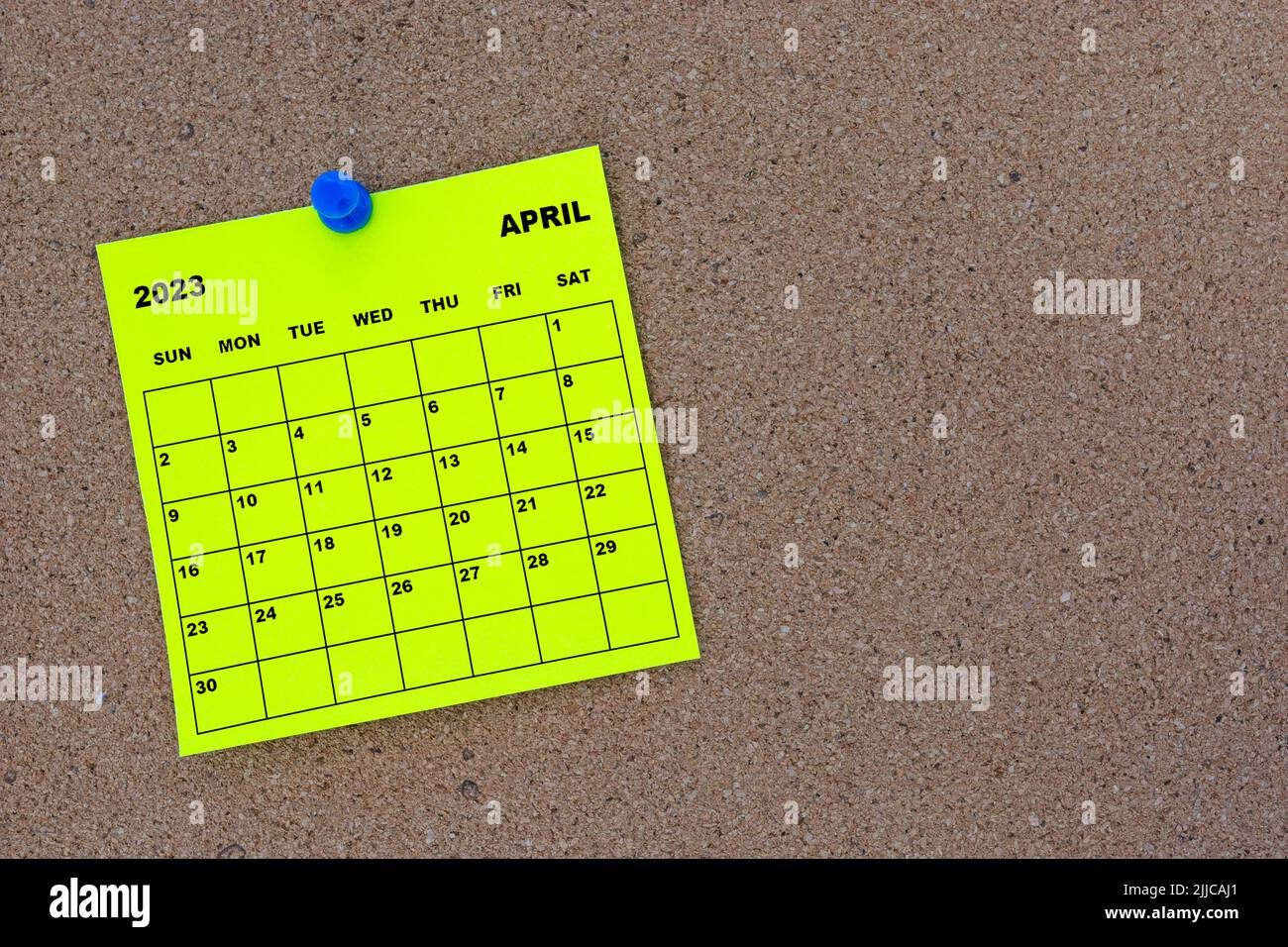 April 2023 yellow sticky note calendar with pin on cork bulletin ...