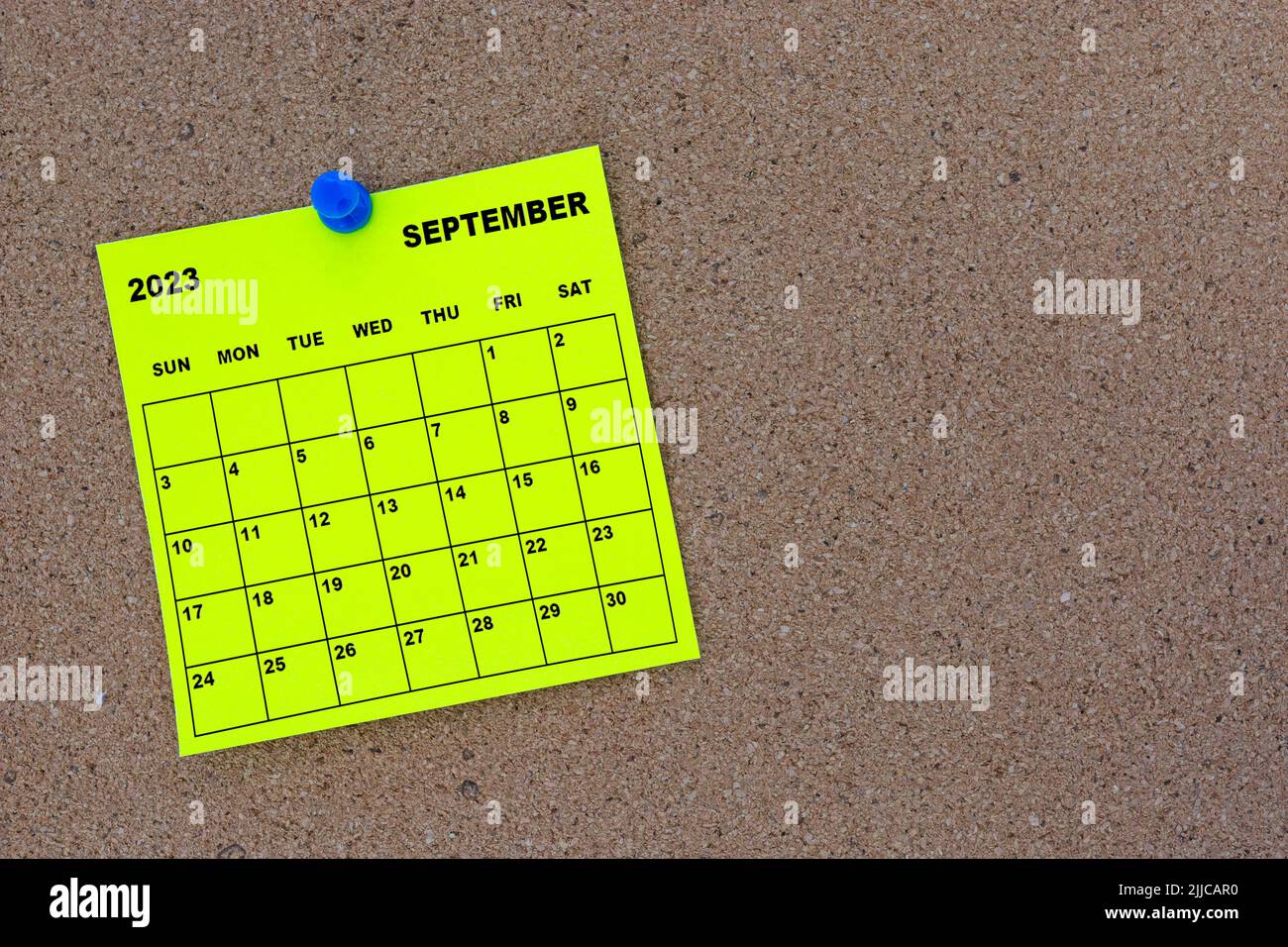September 2023 yellow sticky note calendar with pin on cork bulletin ...