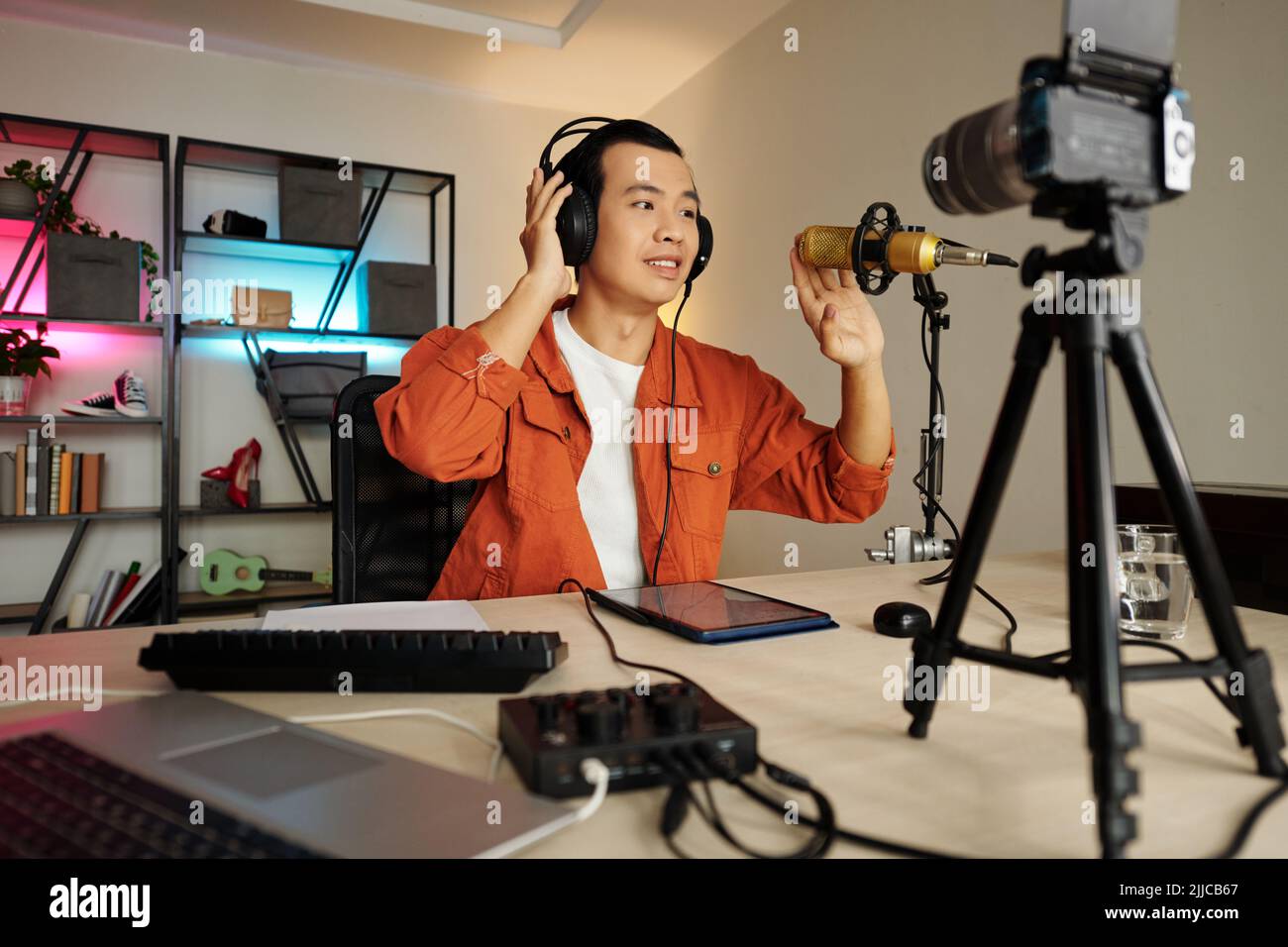 Young Asian blogger in headphones checking if his microphone is working ...