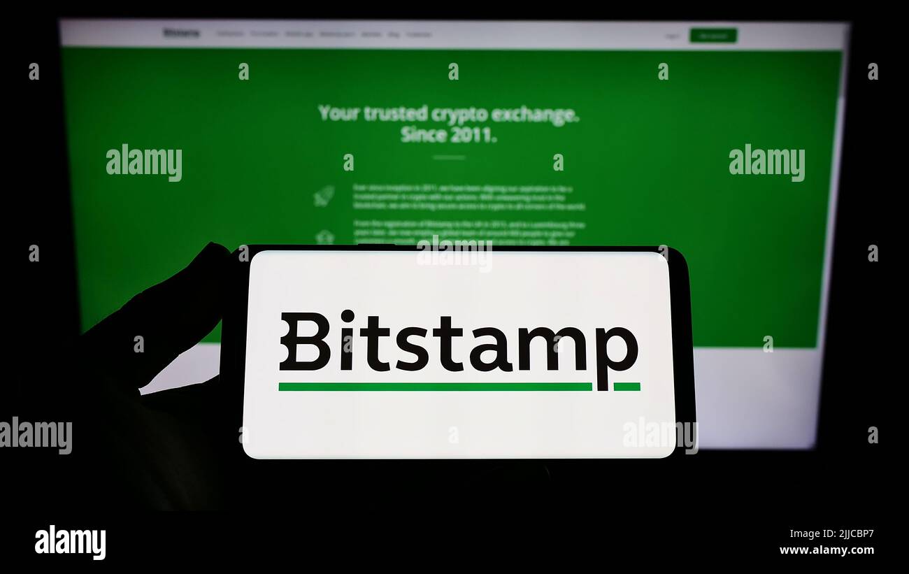 Person holding smartphone with logo of cryptocurrency exchange company ...
