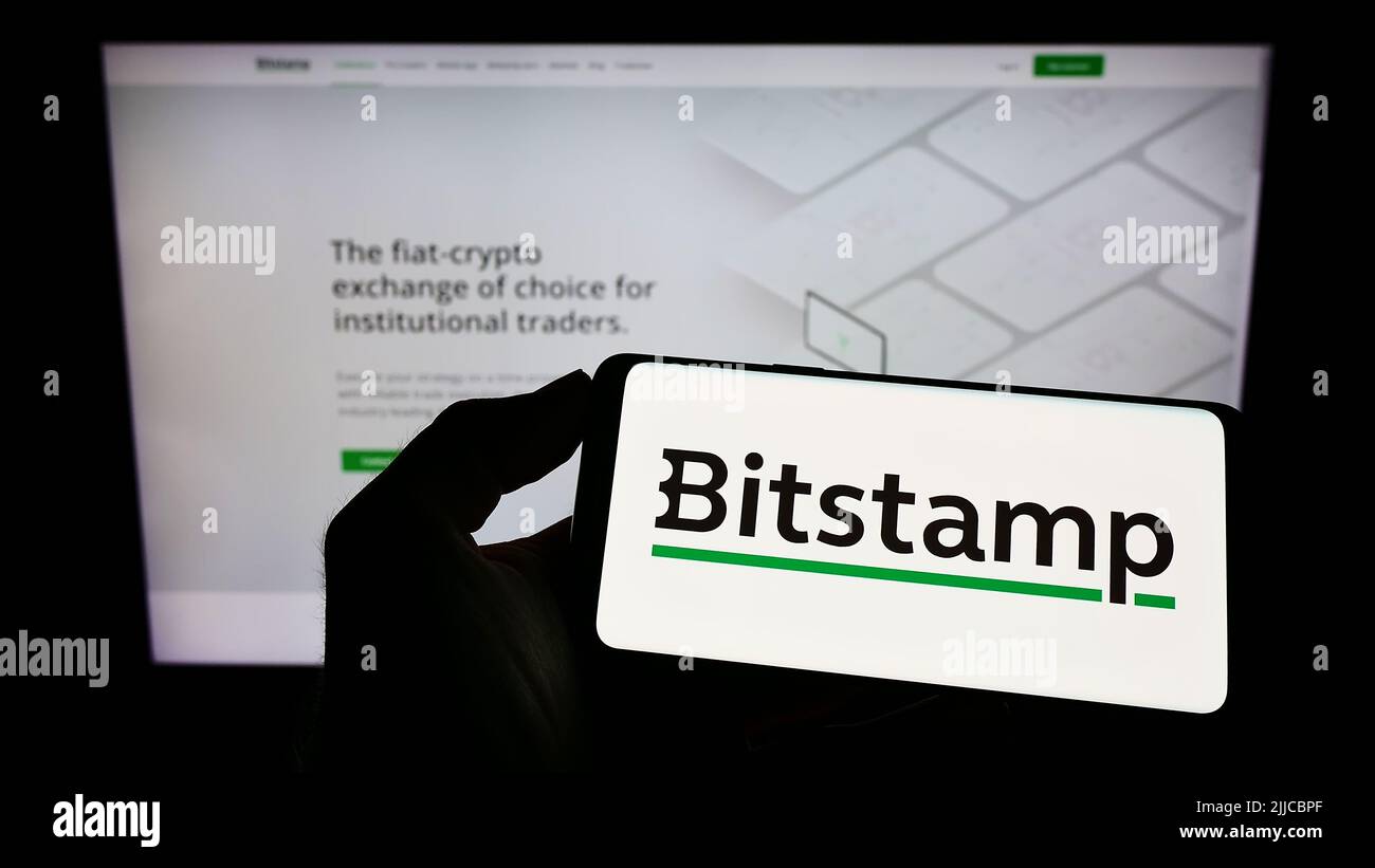 Person holding mobile phone with logo of cryptocurrency exchange ...