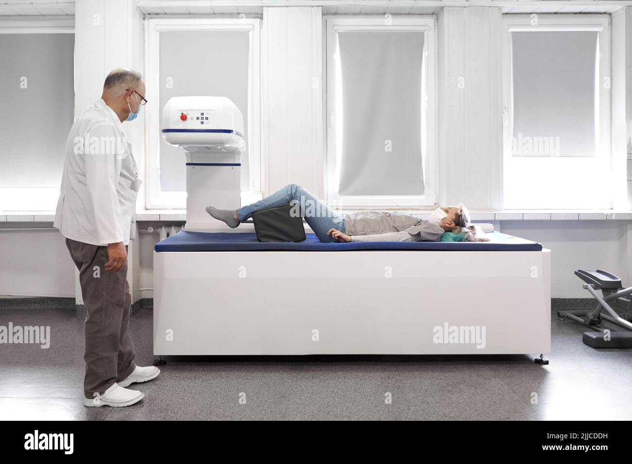 Patient lying on a stretcher of a x-ray machine next to a doctor Stock ...