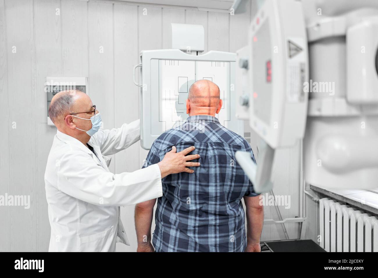 Doctor correctly positioning a patient in front of an x-ray machine ...