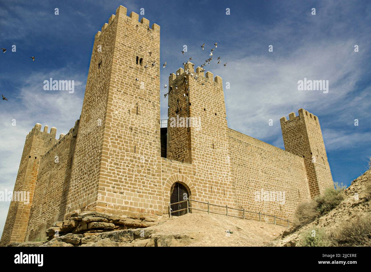 A flock of doves flies around the huge towers of Sadaba Castle in ...