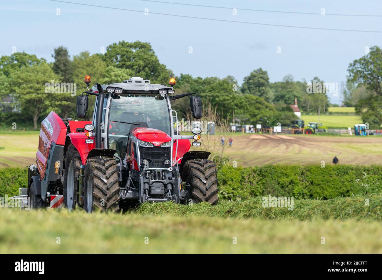 Big baling grass on a meadow using a Massey Ferguson tractor and a ...