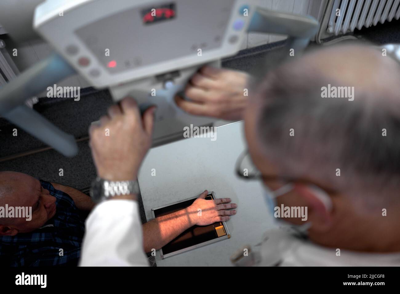 Focus on the hand of a patient on a x-ray plate while a doctor in ...