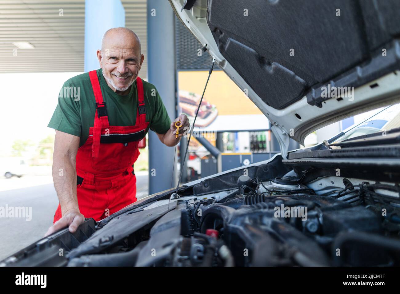 A senior mechanic checking the oil level in the car engine Stock Photo ...