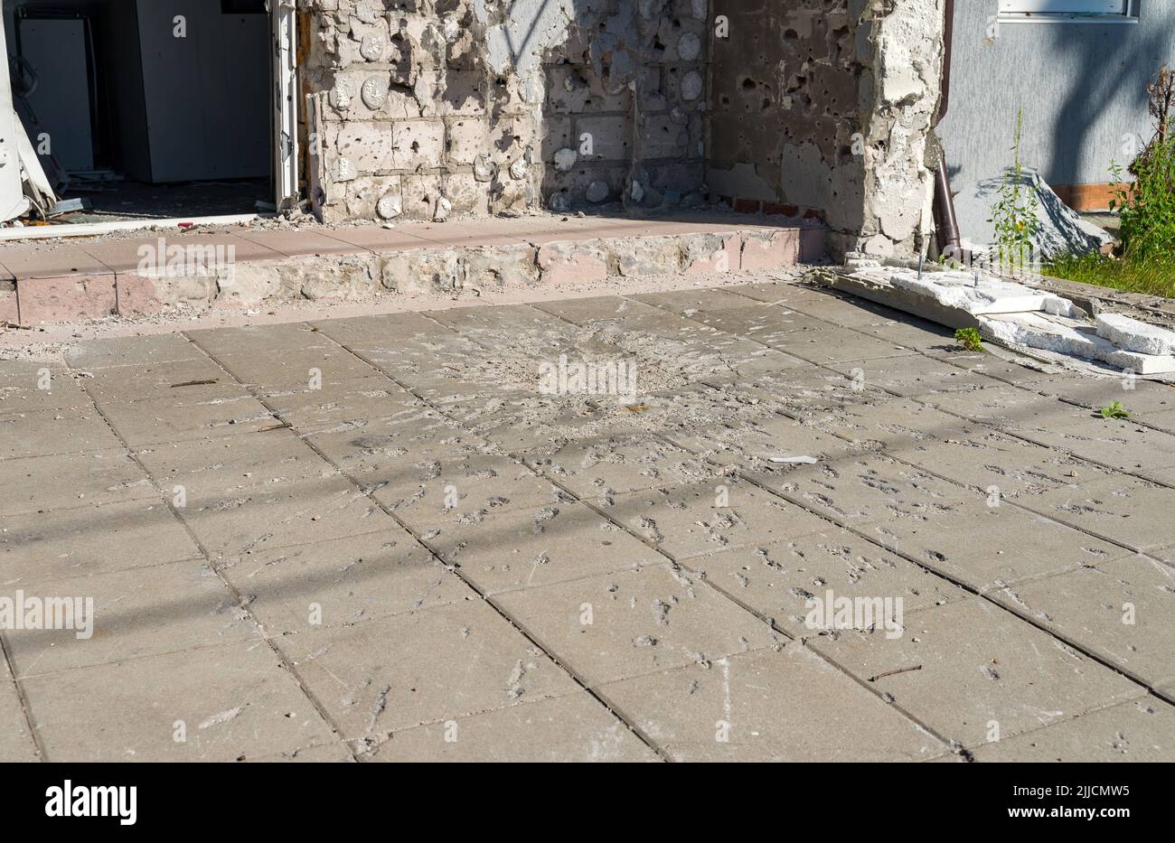 Traces on paving slabs from a shell hit. Part of the building destroyed ...