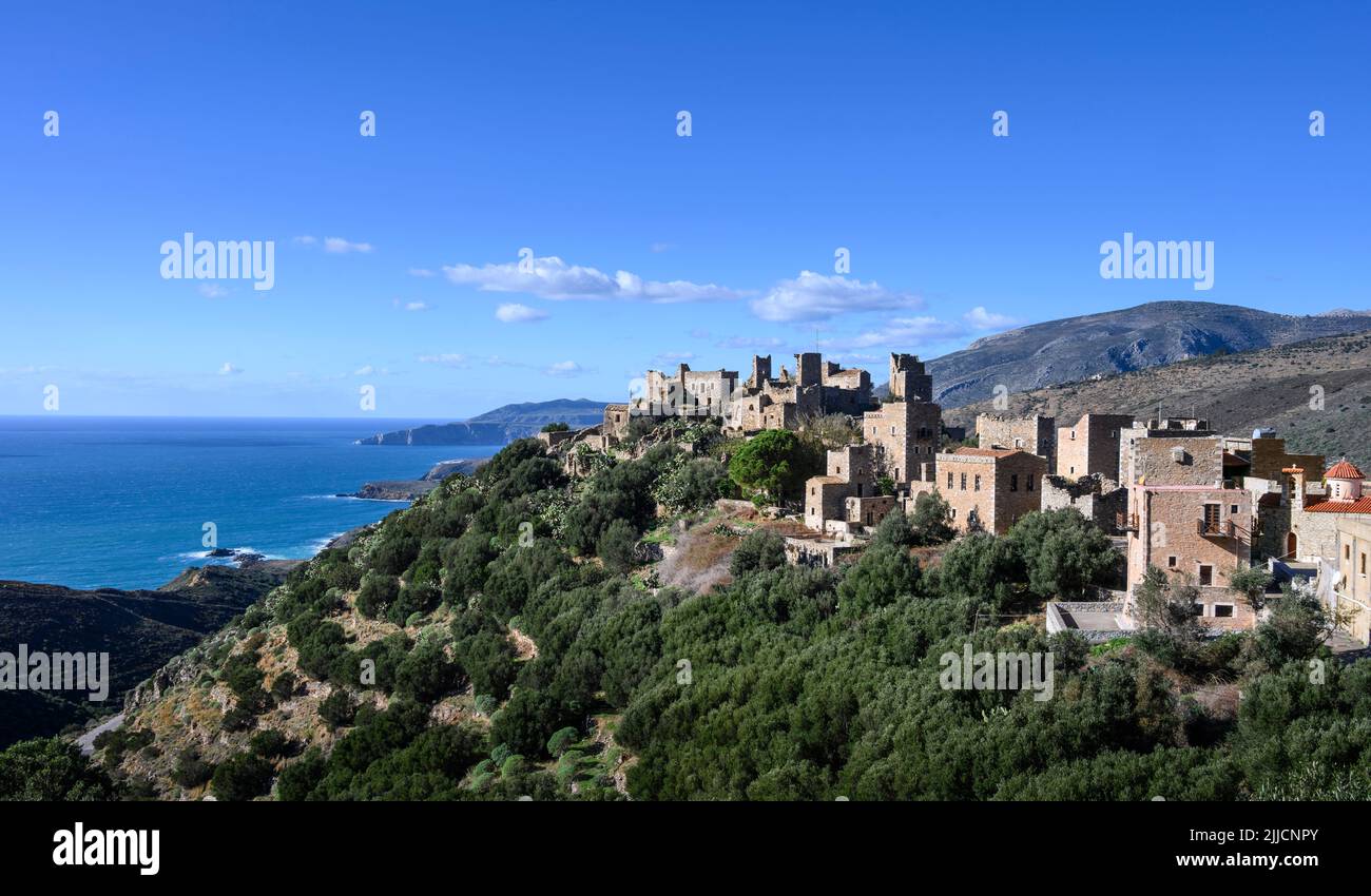 The stone towers and ruined houses of Vathia with the dramatic coast of ...