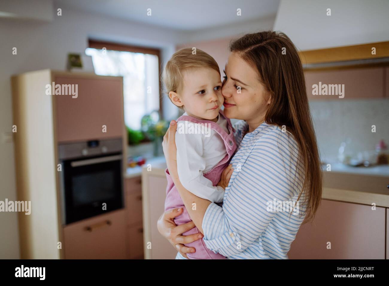 A young mother hugging her little daughter at home, lifting her up Stock Photo - Alamy