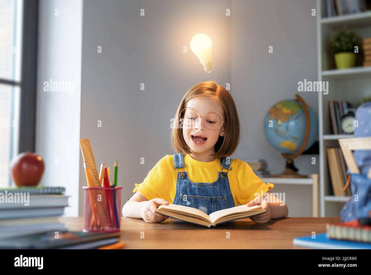 Back to school! Happy cute industrious child is sitting at a desk ...